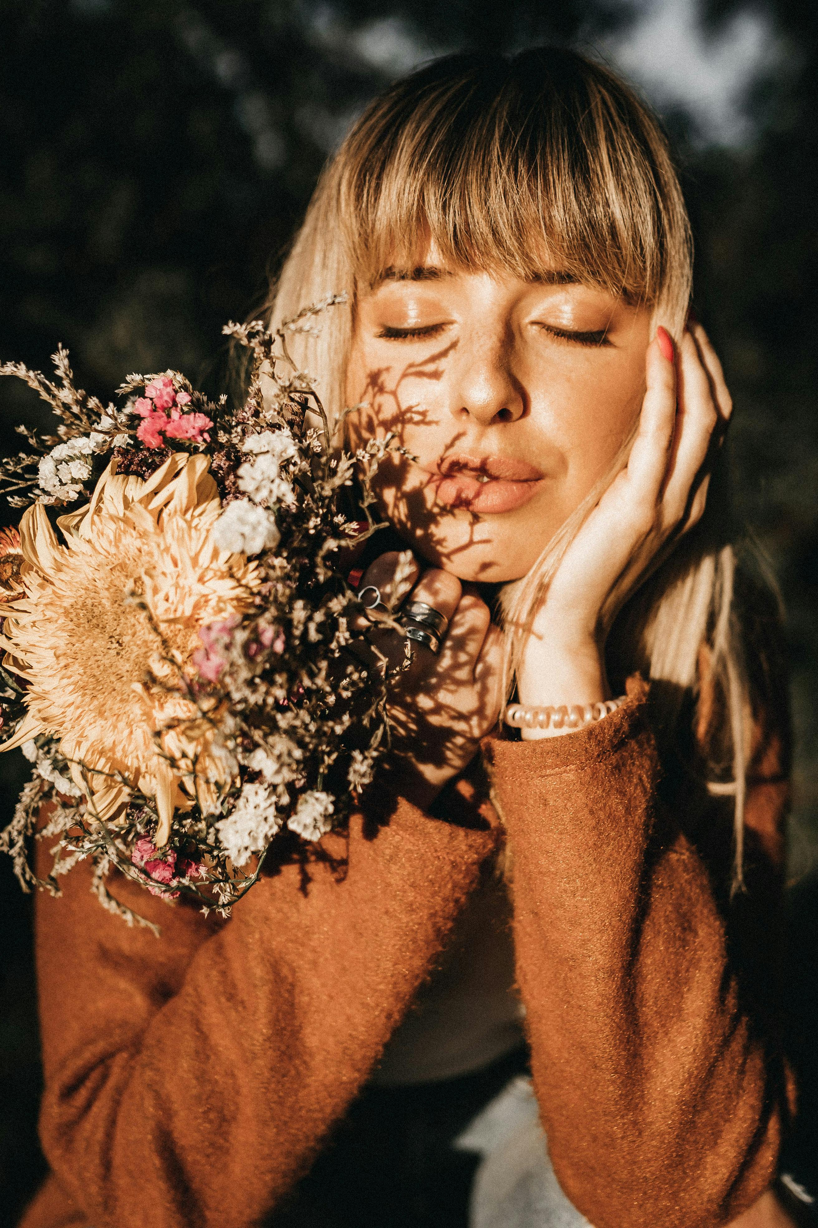 Reflective woman covering eye with dry bouquet in park · Free Stock Photo