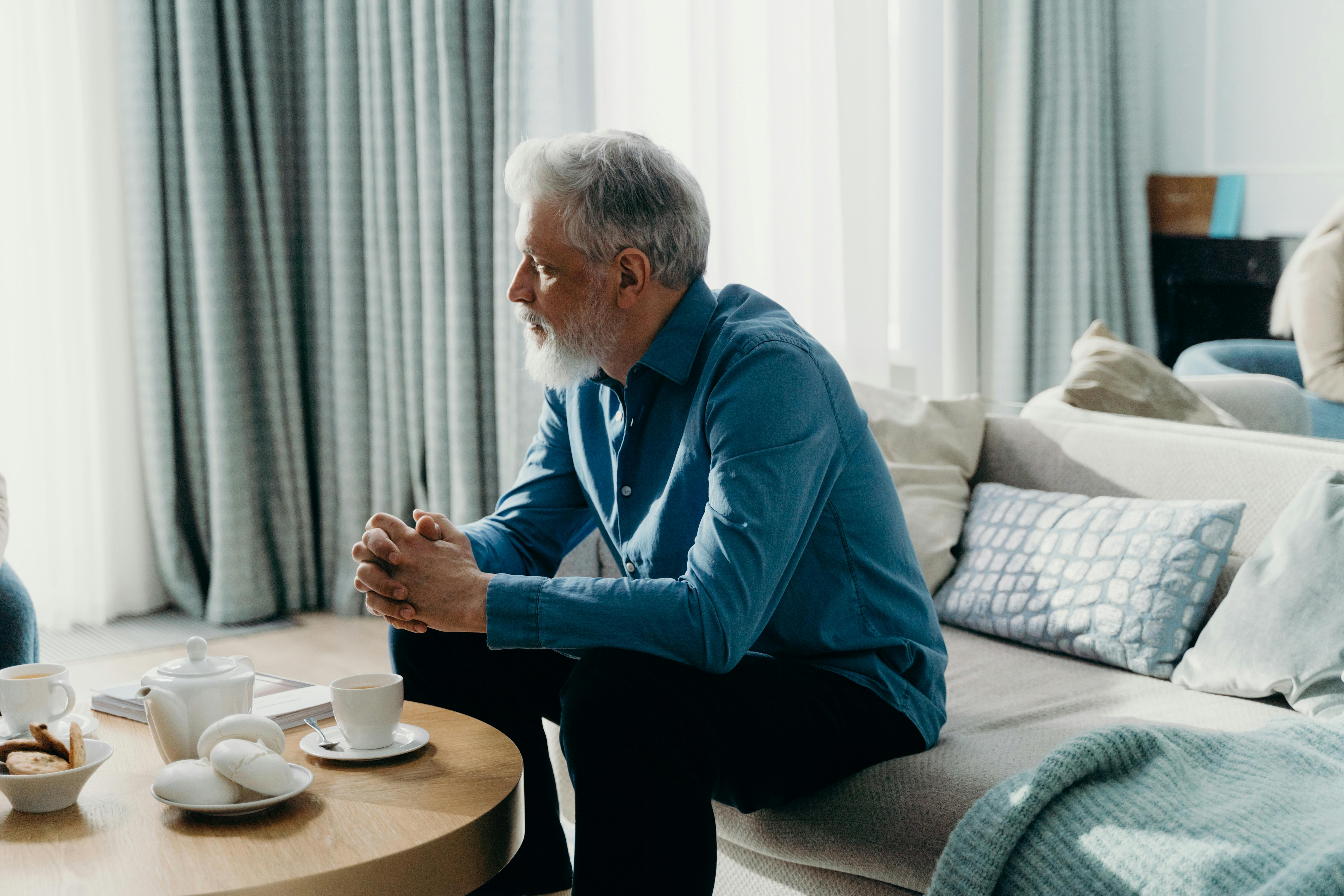 Elderly Man in a Blue Shirt Sitting on a Sofa · Free Stock Photo