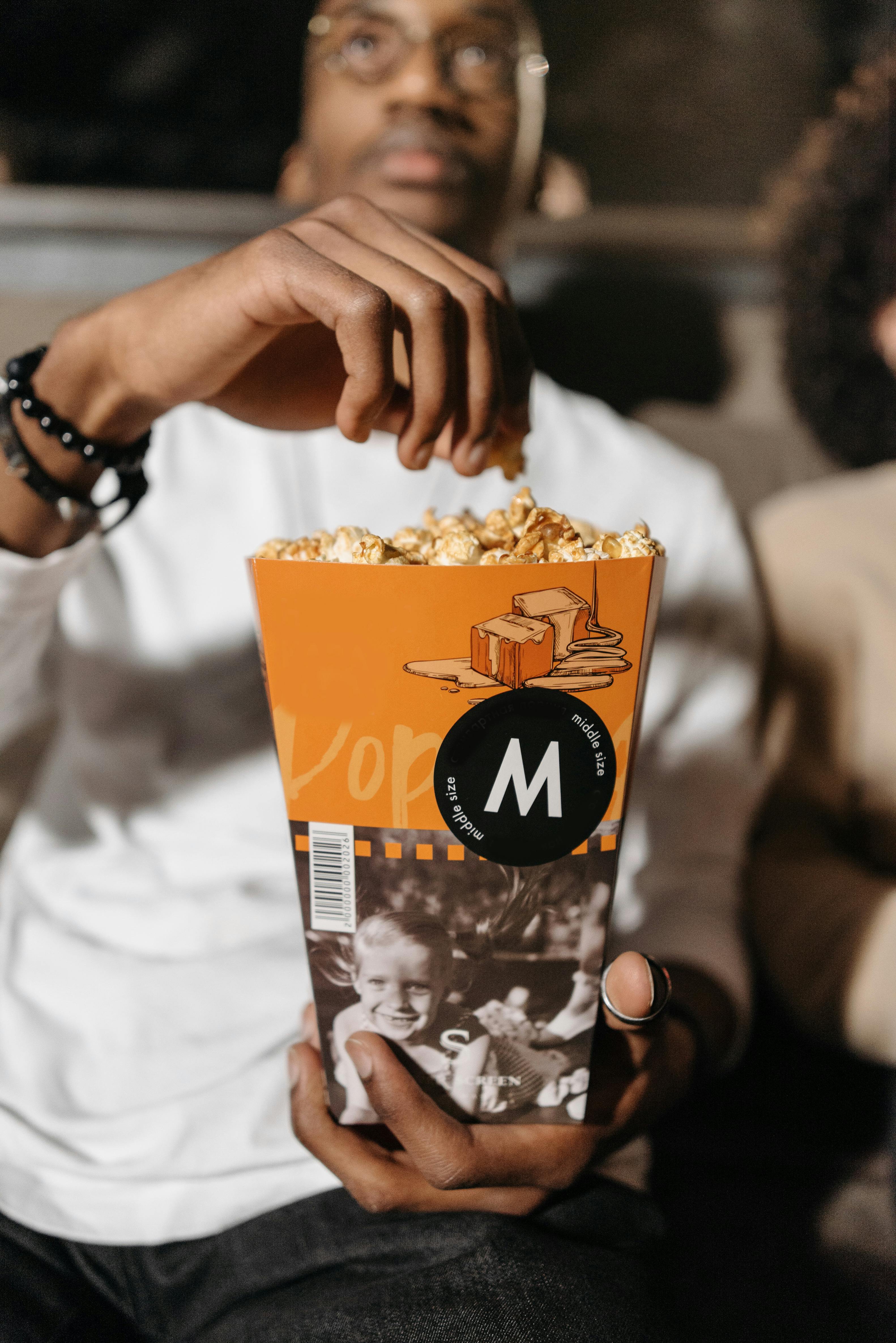 Photo of a Man Holding a Bucket of Caramel Popcorn · Free Stock Photo