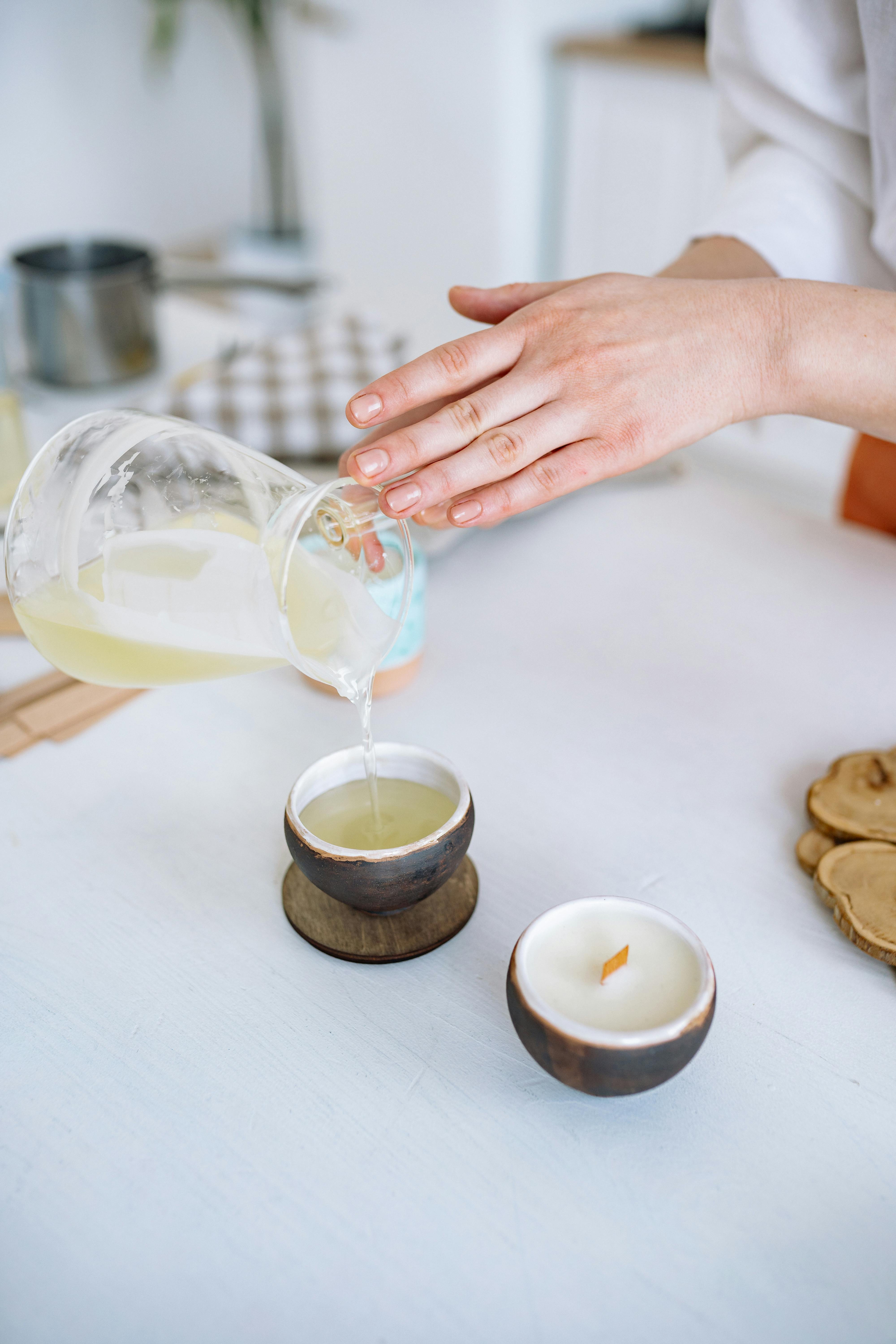 A Person Pouring a Clear Liquid on a Round Pot · Free Stock Photo