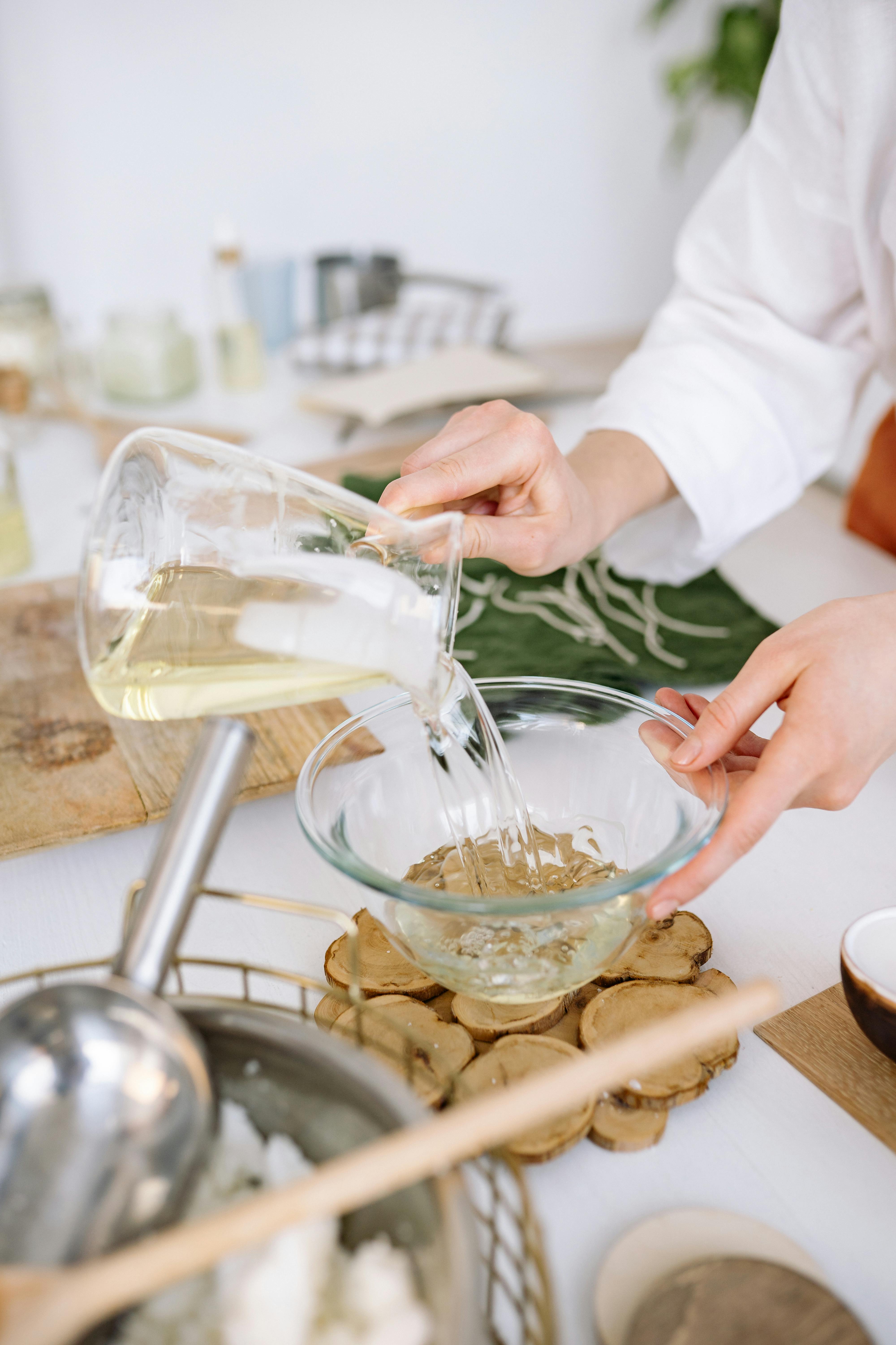 Person Pouring Clear Liquid in Glass Bowl · Free Stock Photo