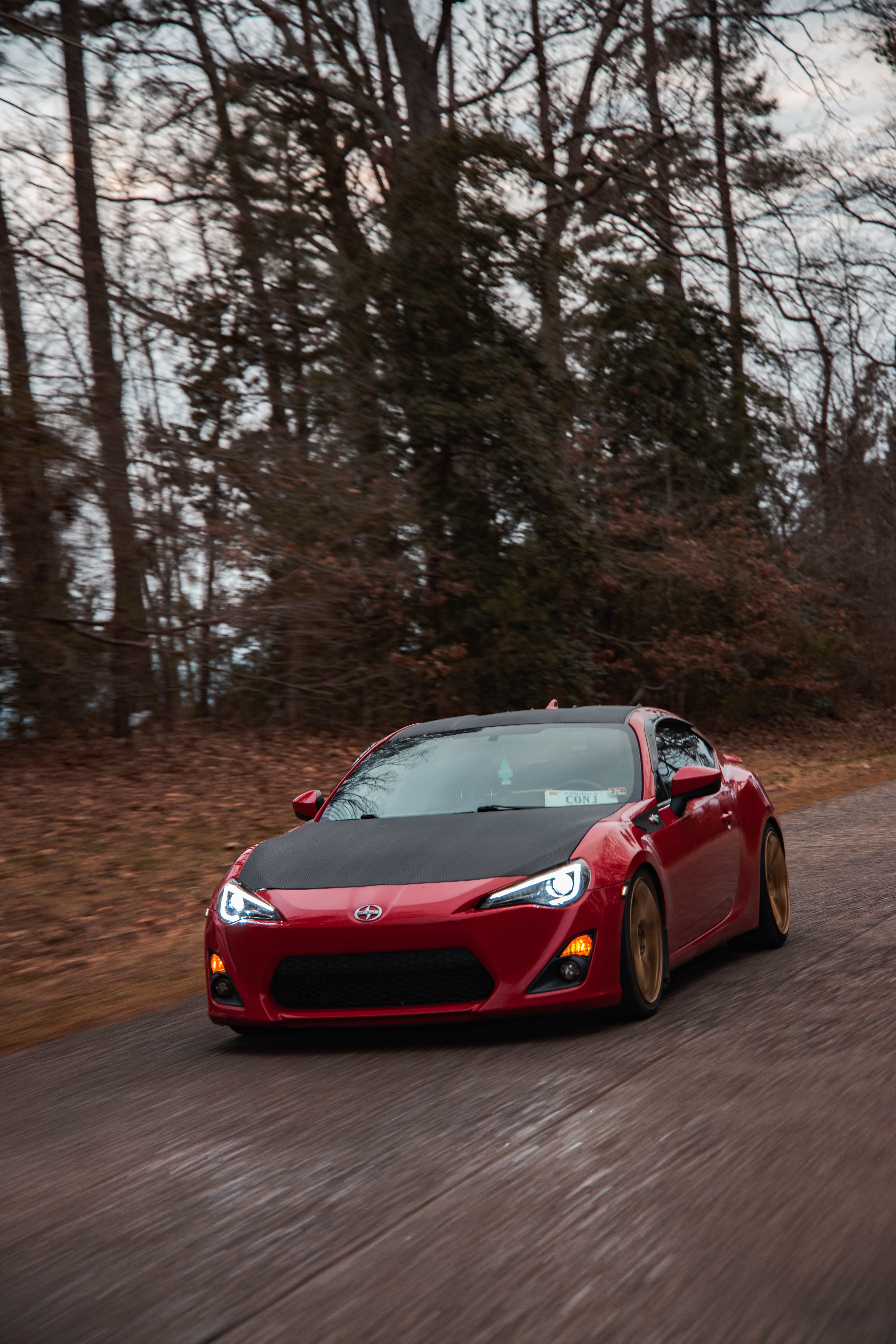 Red Toyota Car Driving on Concrete Road · Free Stock Photo