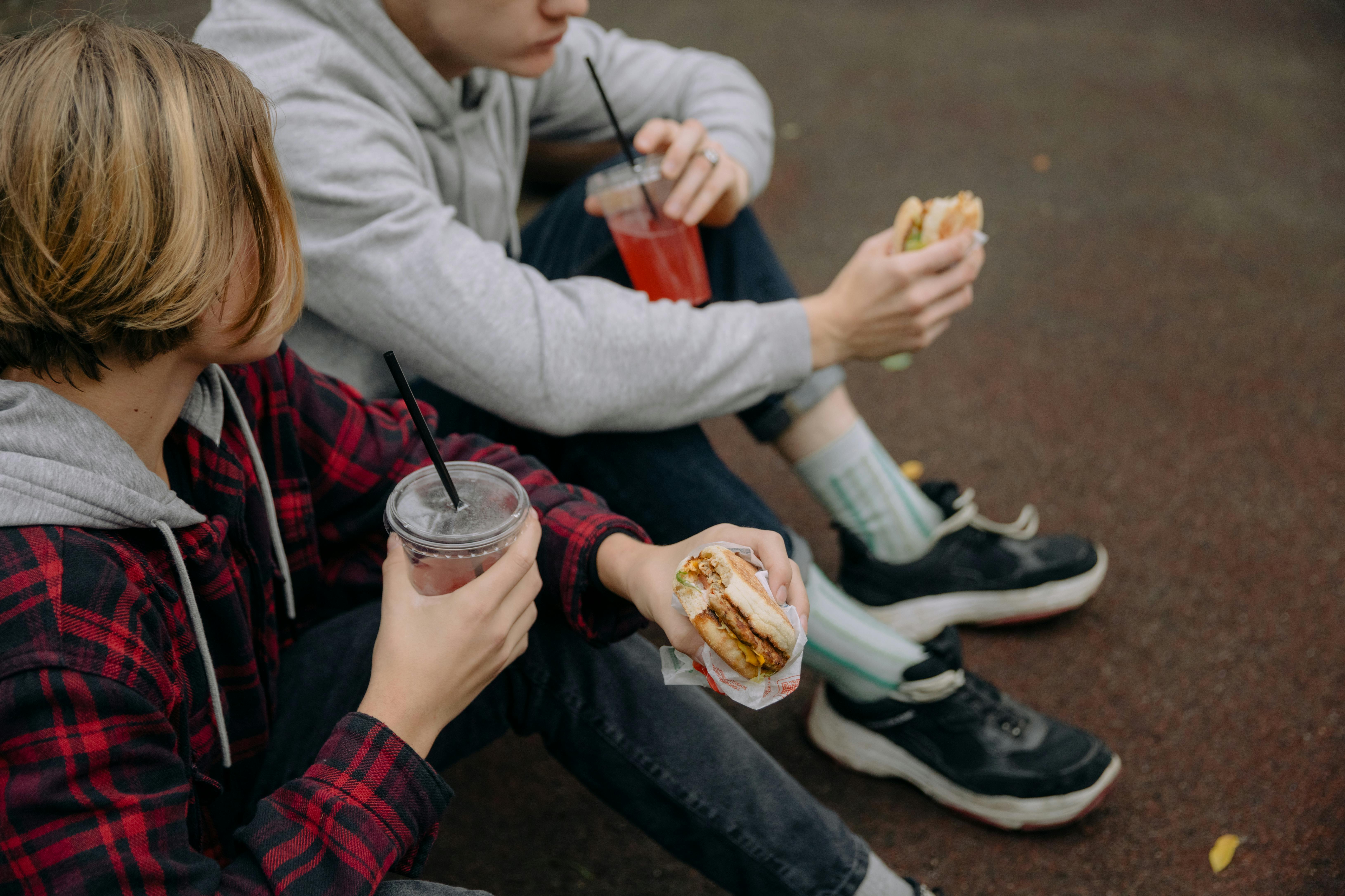 Men Eating Snacks while Sitting on a Pavement · Free Stock Photo