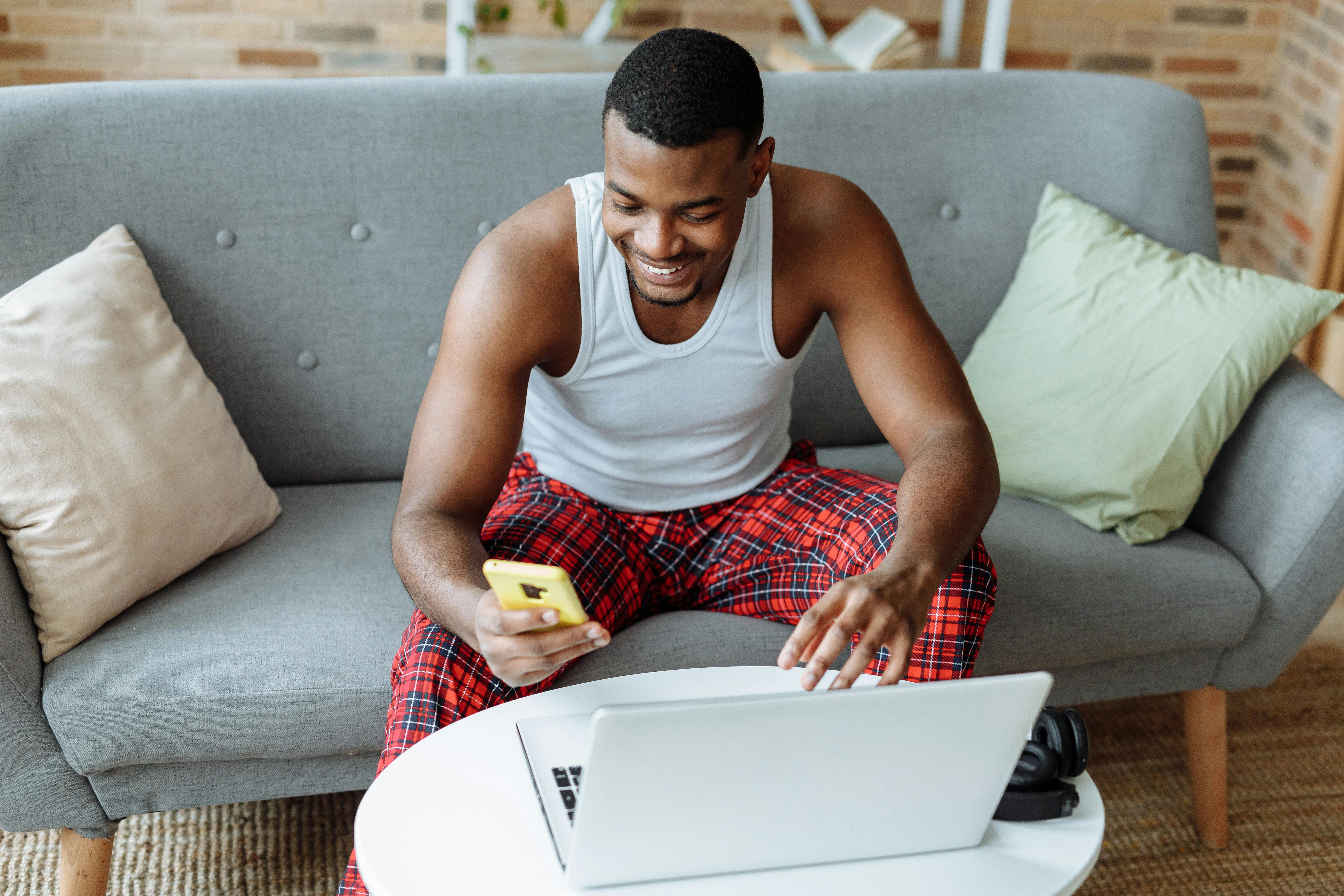 A Man Using a Mobile Phone While in Front of a Laptop · Free Stock Photo