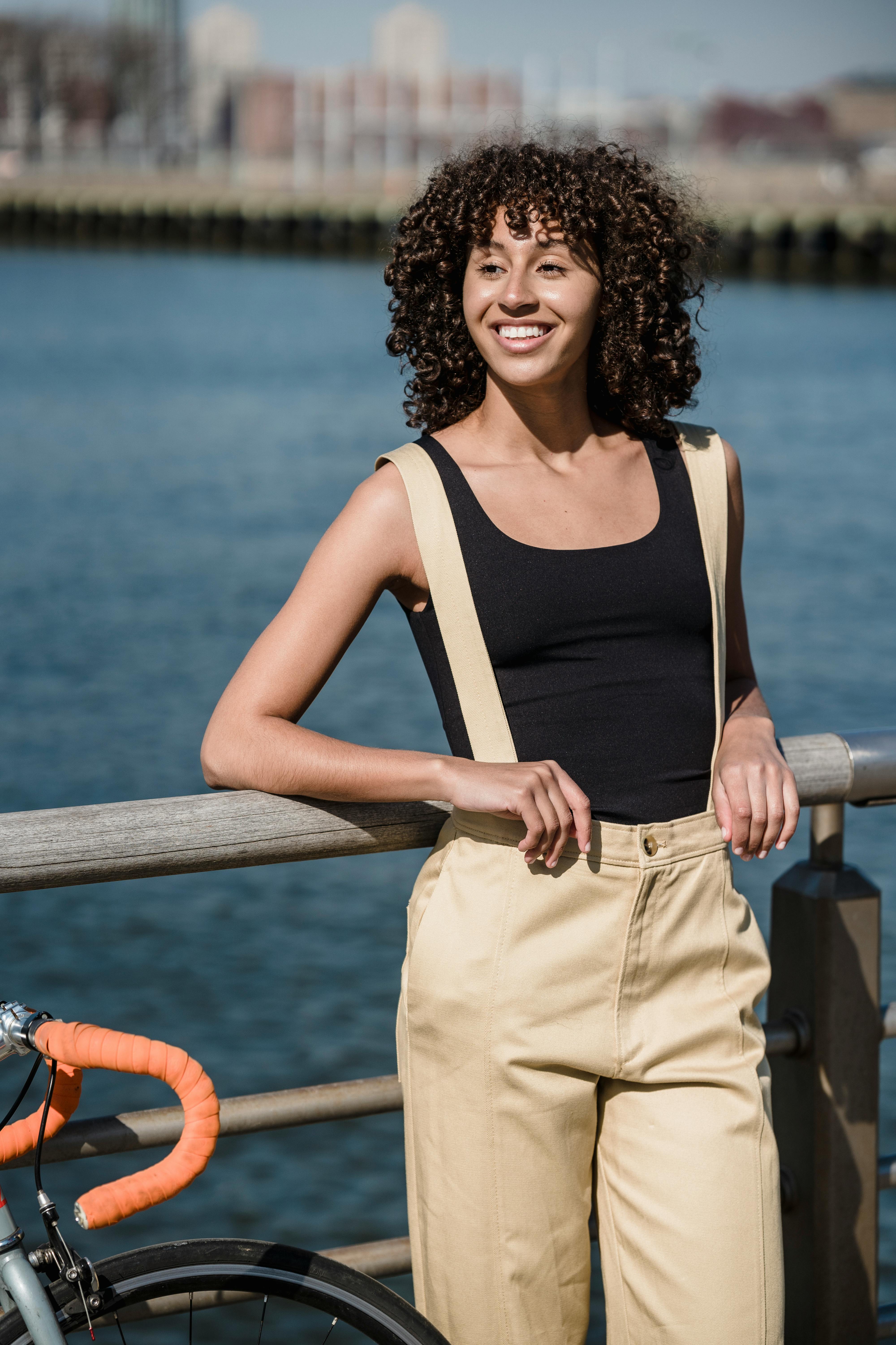 Black woman in jacket leaning on railing near building · Free Stock Photo