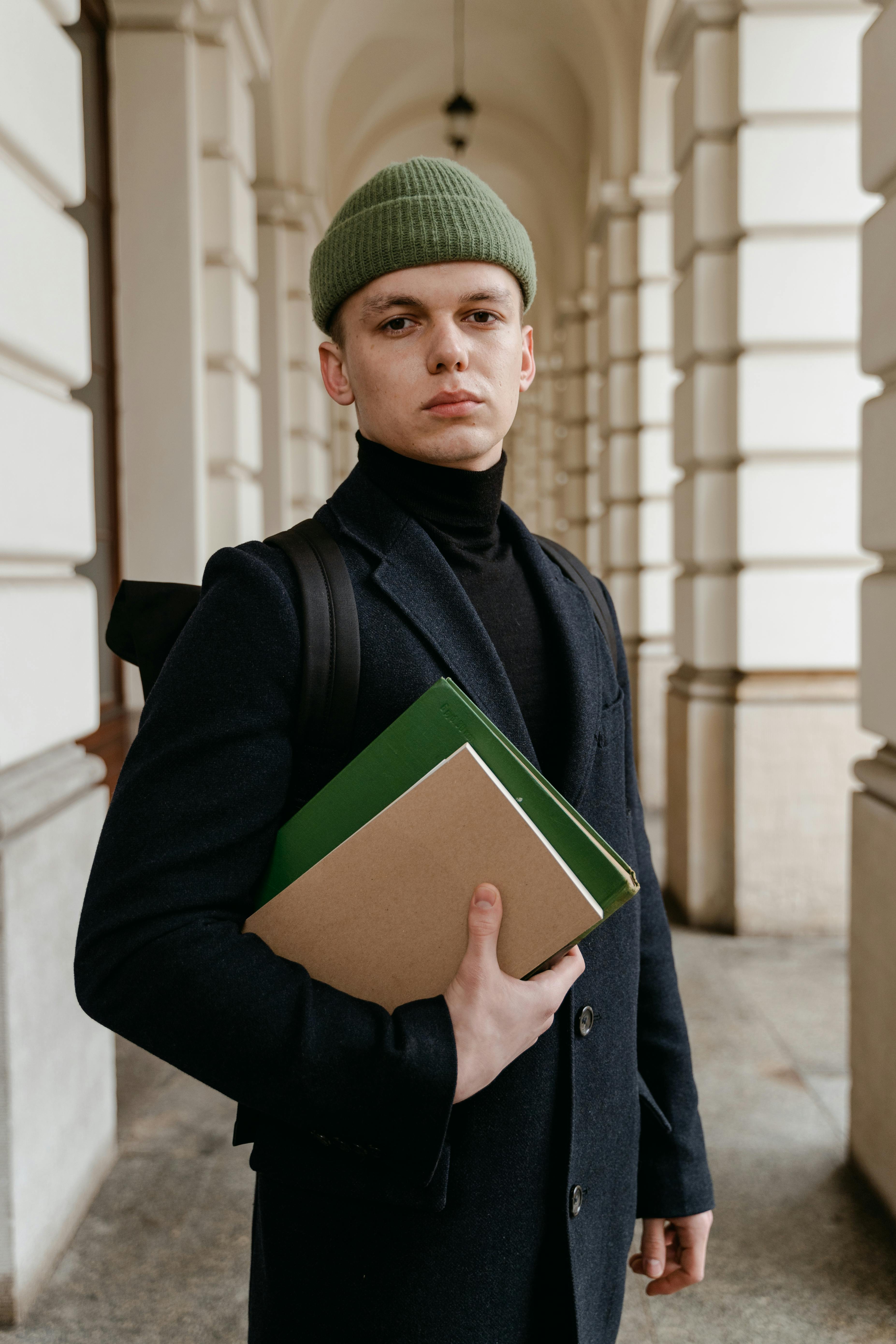 A College Student Holding a Book and Smiling · Free Stock Photo