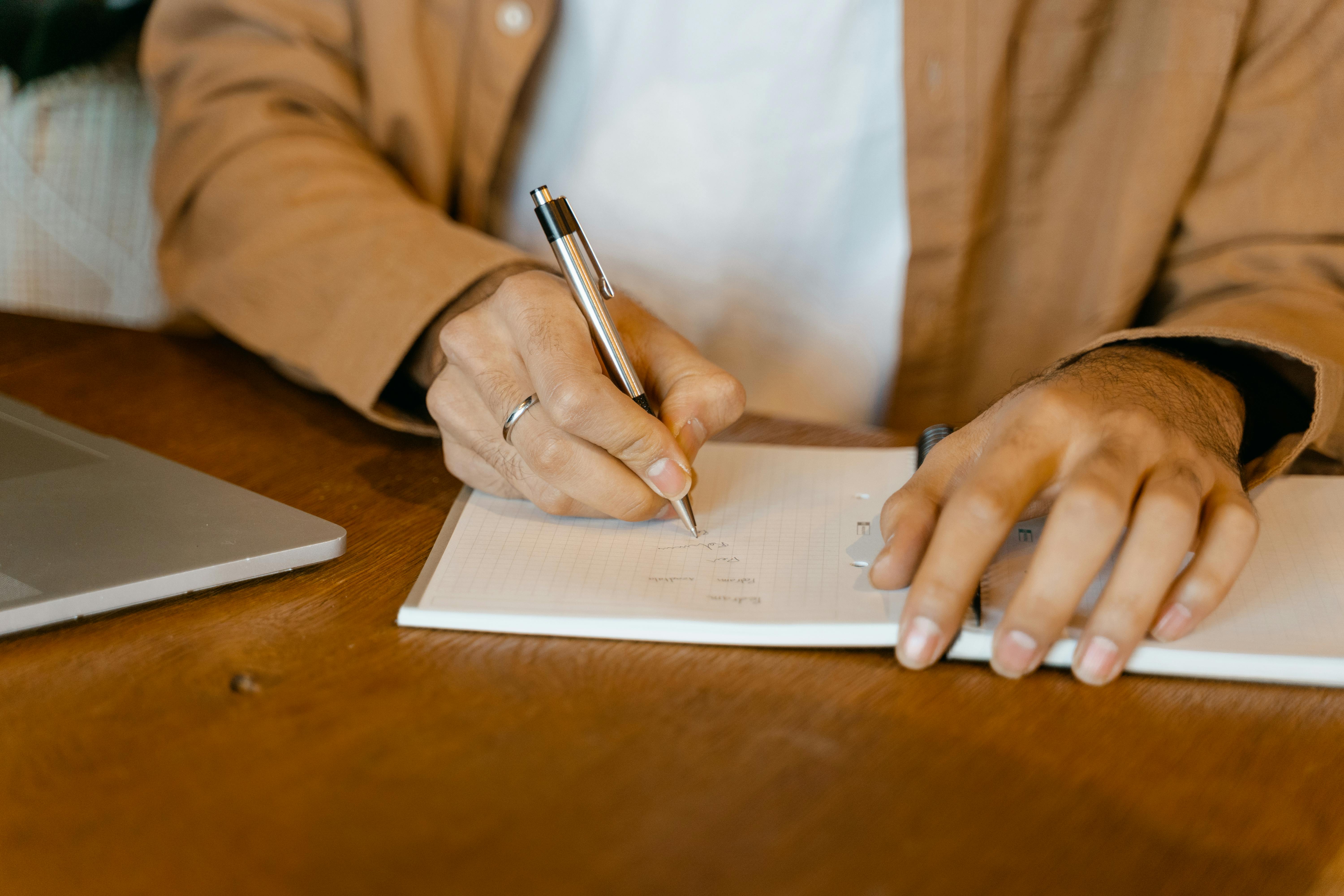 Person Writing on Notebook · Free Stock Photo