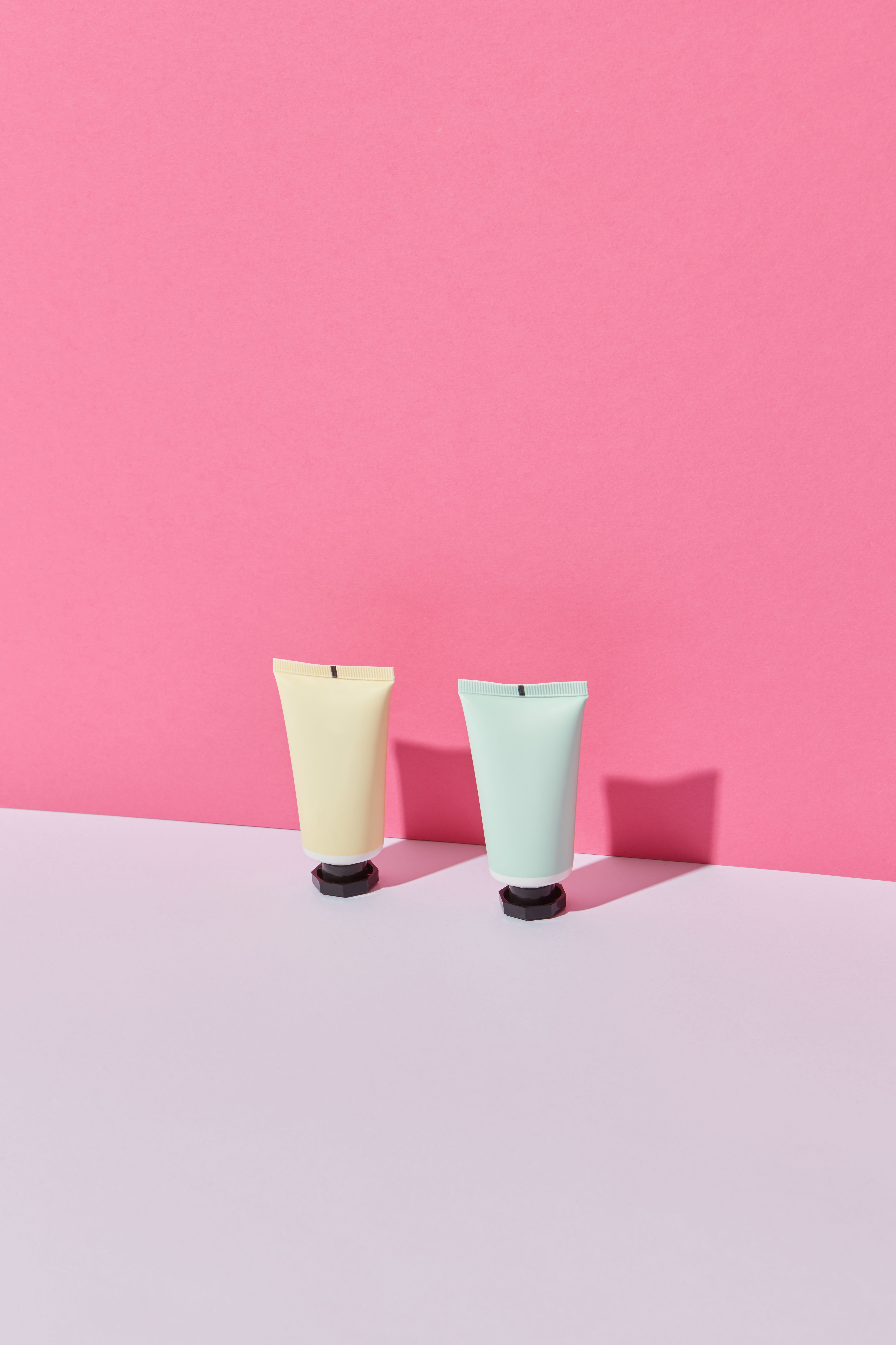 Green and Yellow Plastic Tube Bottles on Pink Background · Free Stock Photo