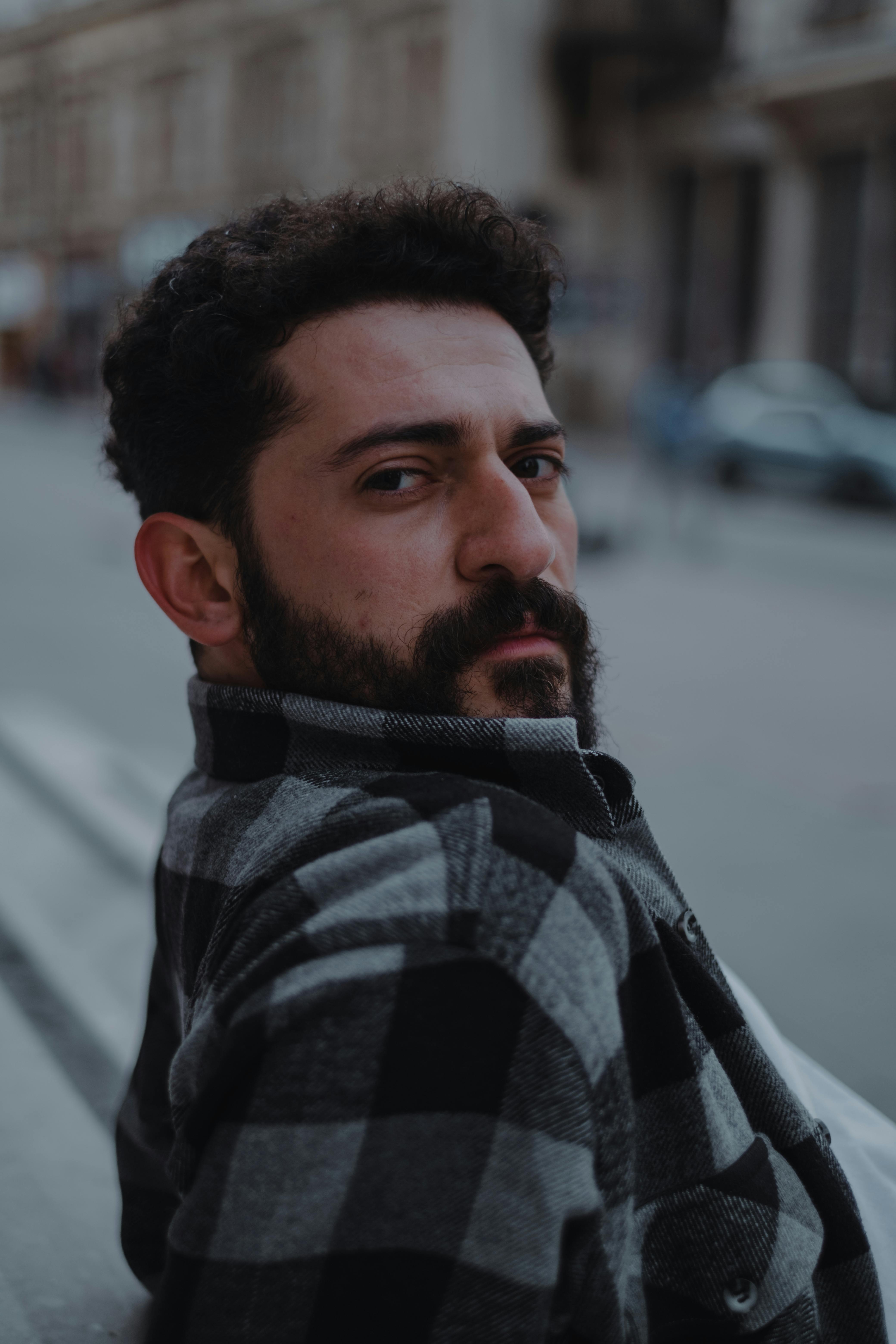 Wistful man leaning on door of red building · Free Stock Photo