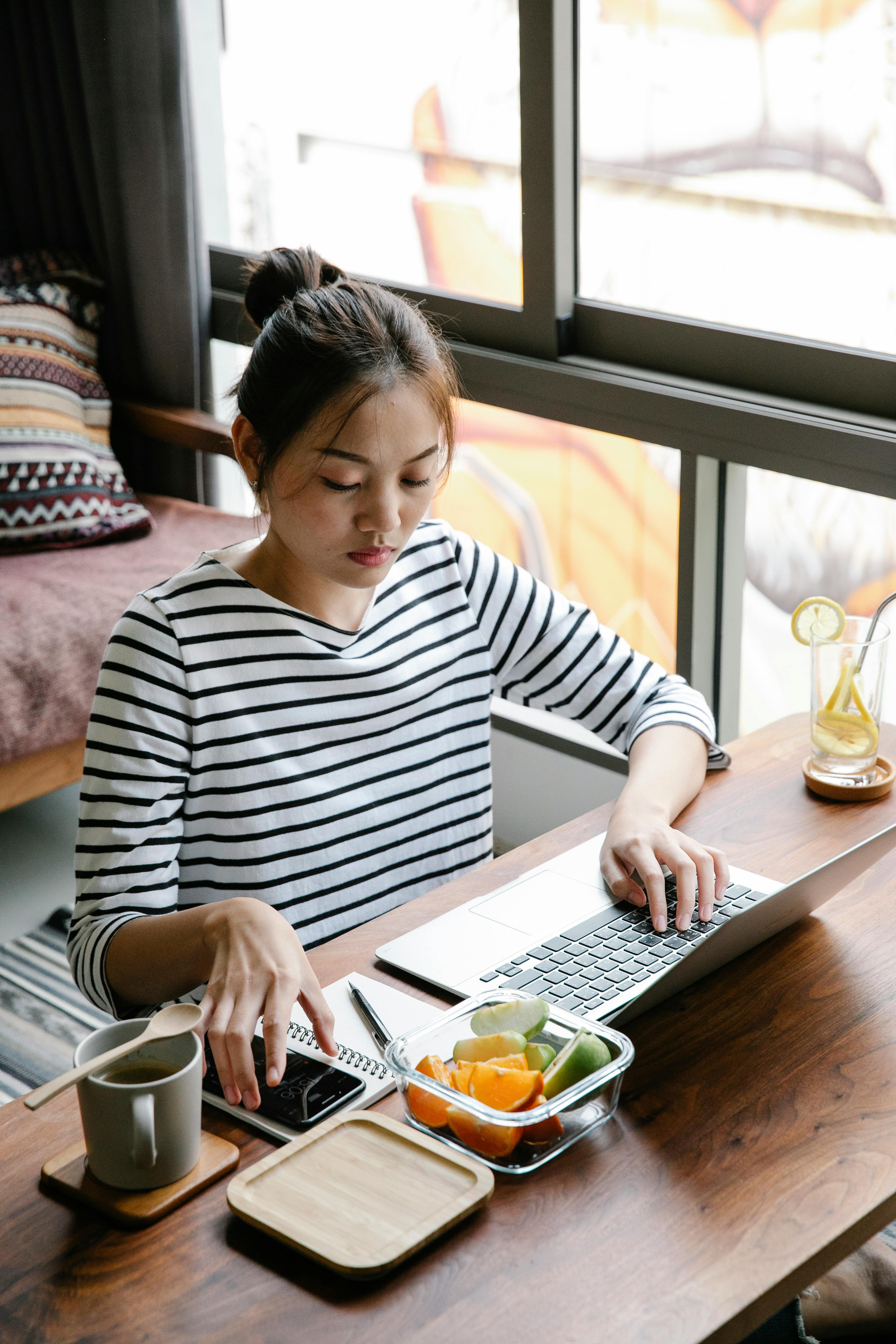 Asian woman using laptop in cafe · Free Stock Photo