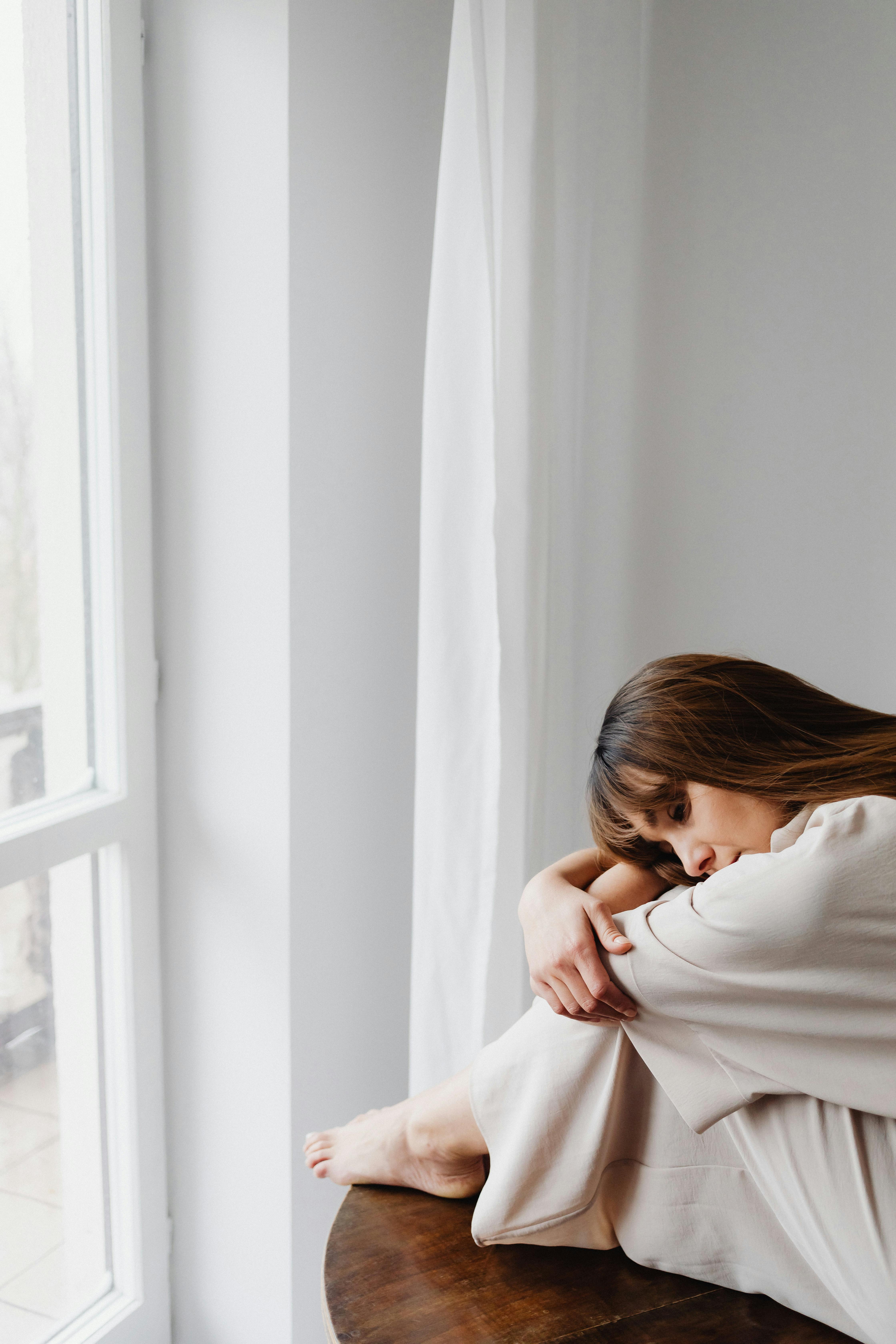 Sad Woman on Table near Window · Free Stock Photo