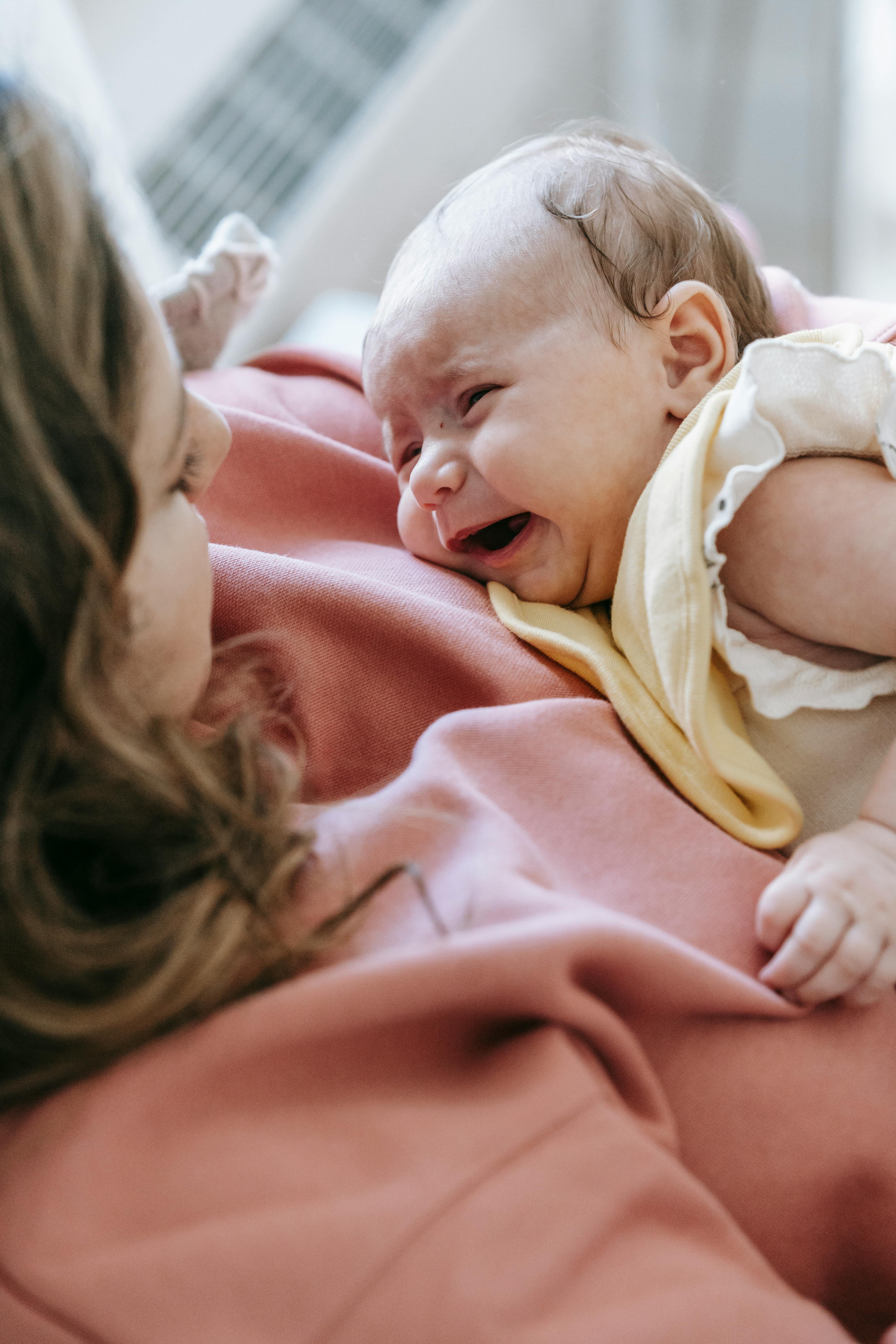 Crop young mother hugging adorable crying baby · Free Stock Photo