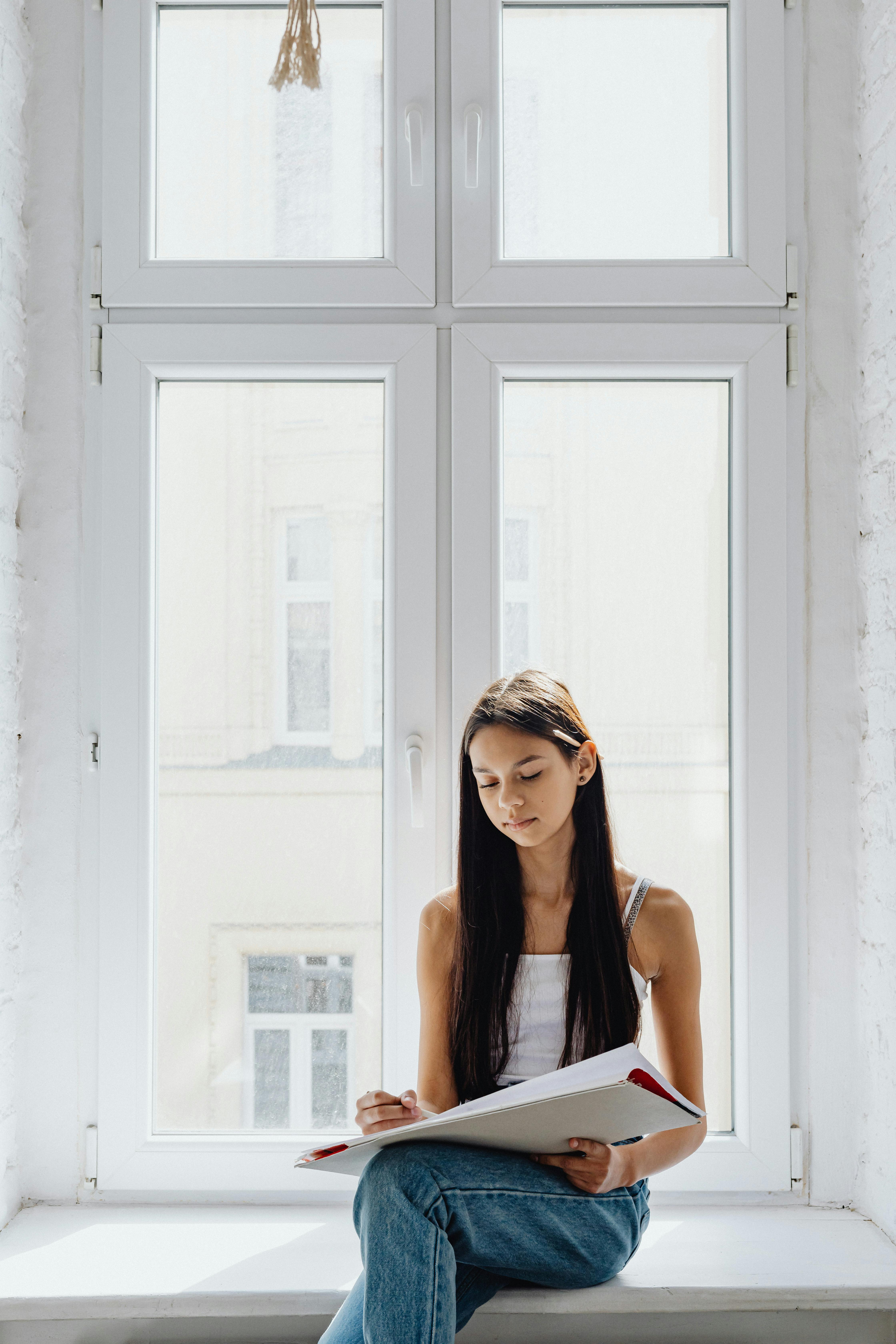 Woman Sitting on Pillow by the Window · Free Stock Photo