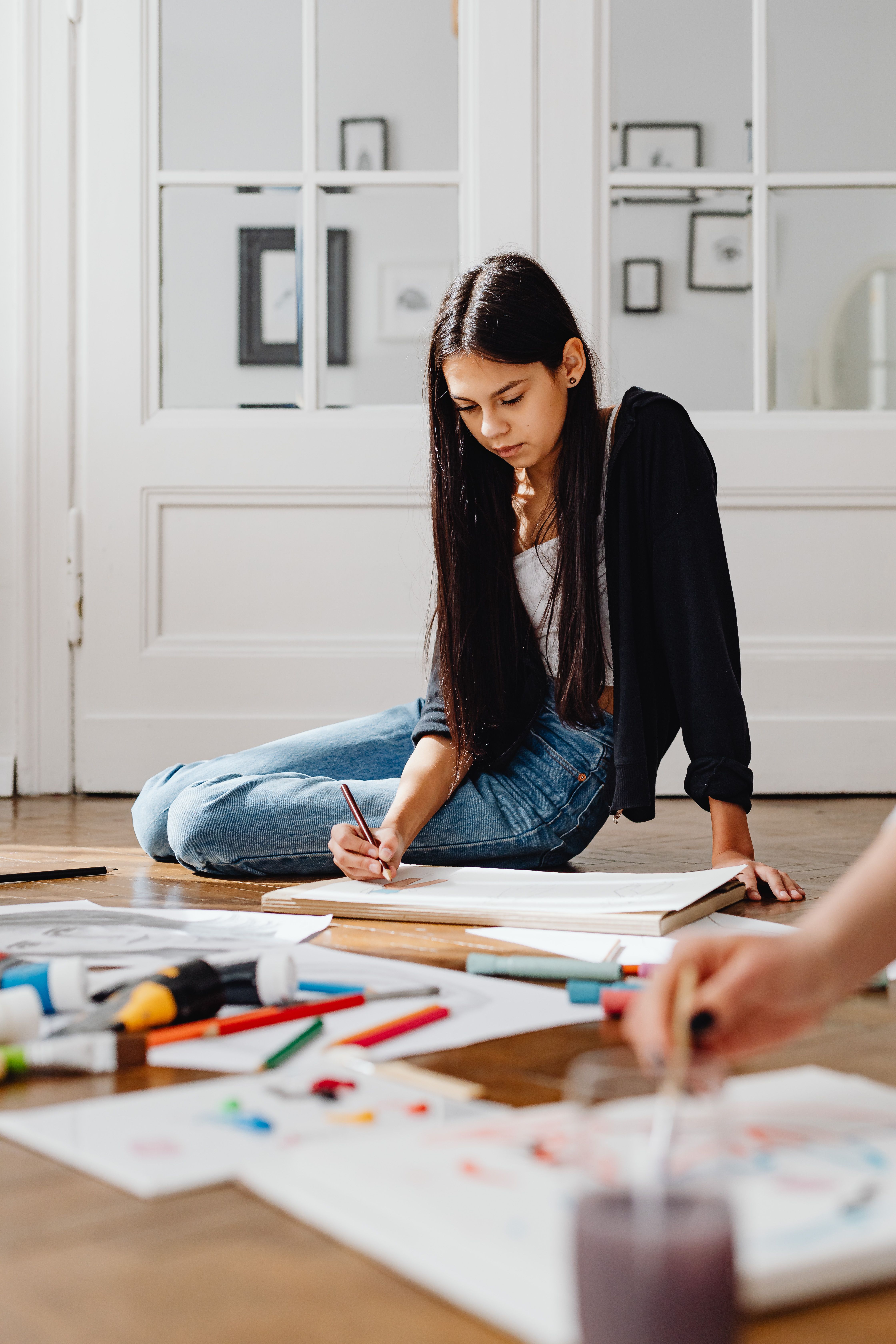 Woman Sitting on the Floor while Coloring on Paper · Free Stock Photo