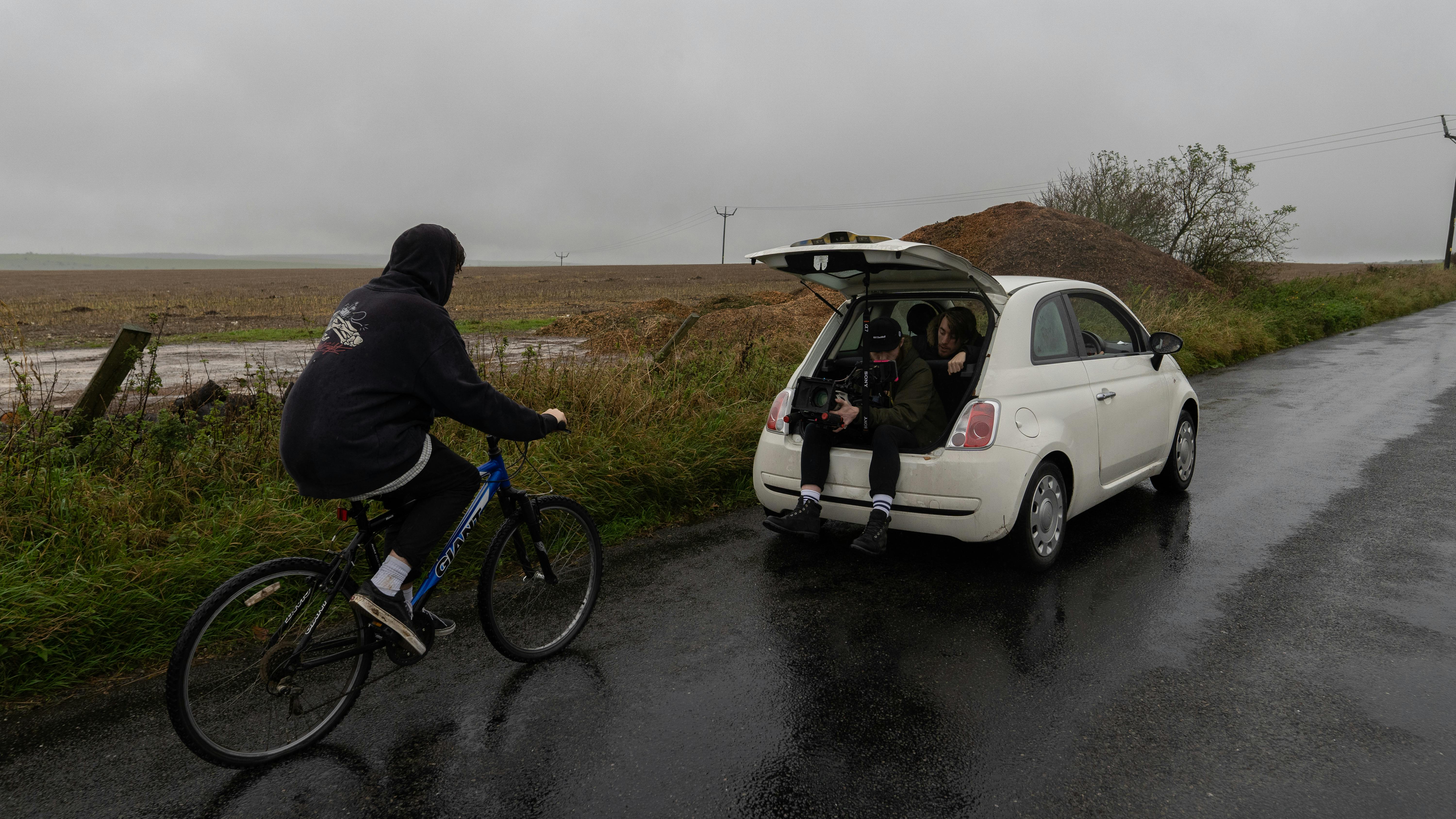 A Cameraman Filming a Man Wearing Raincoat while Riding a Bike · Free ...