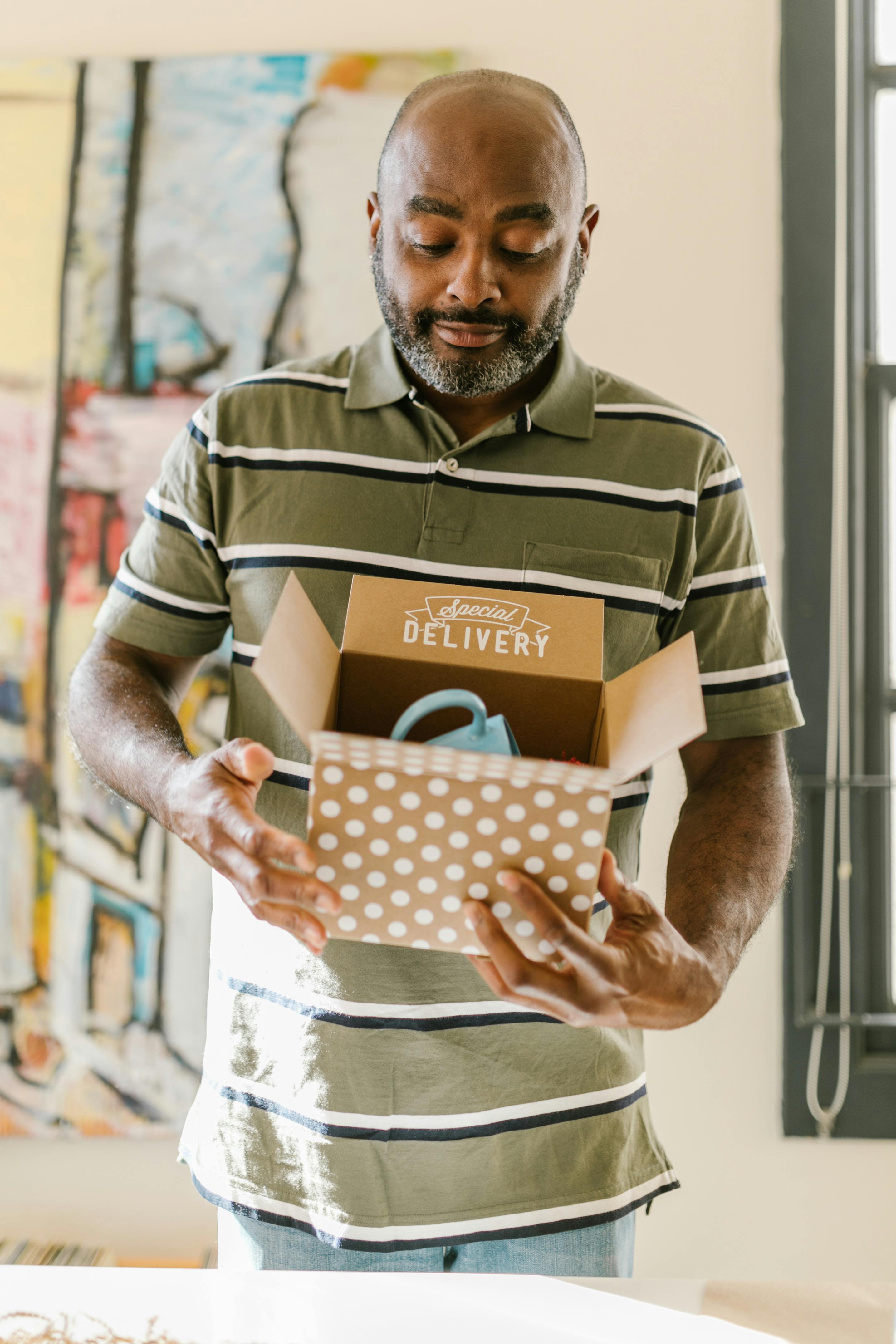 A Man Holding a Box with a Mug · Free Stock Photo
