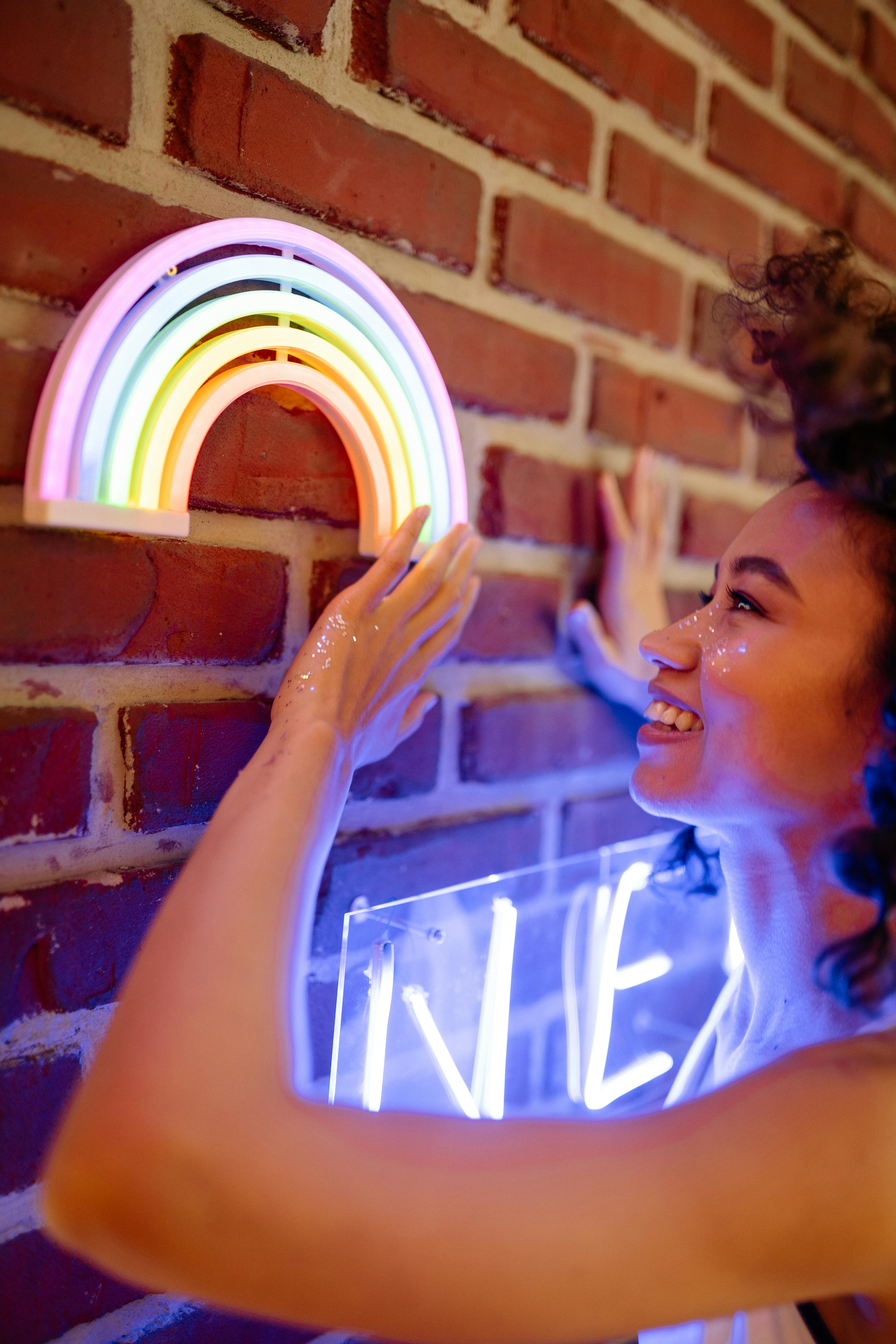 A Young Woman Touching a Neon Light Rainbow · Free Stock Photo