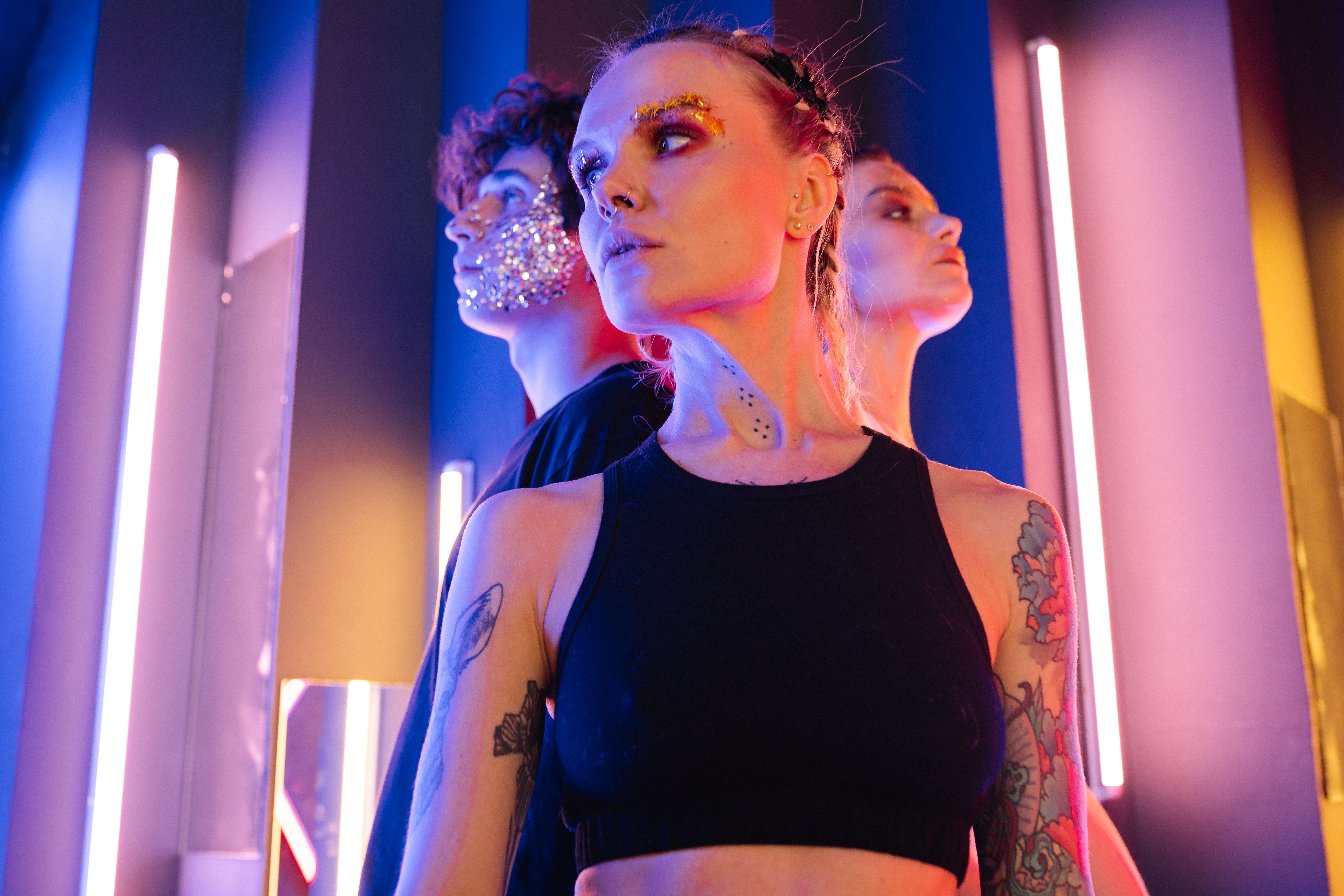 A Group of People Wearing Creative Makeup Standing Near Neon Lights ...