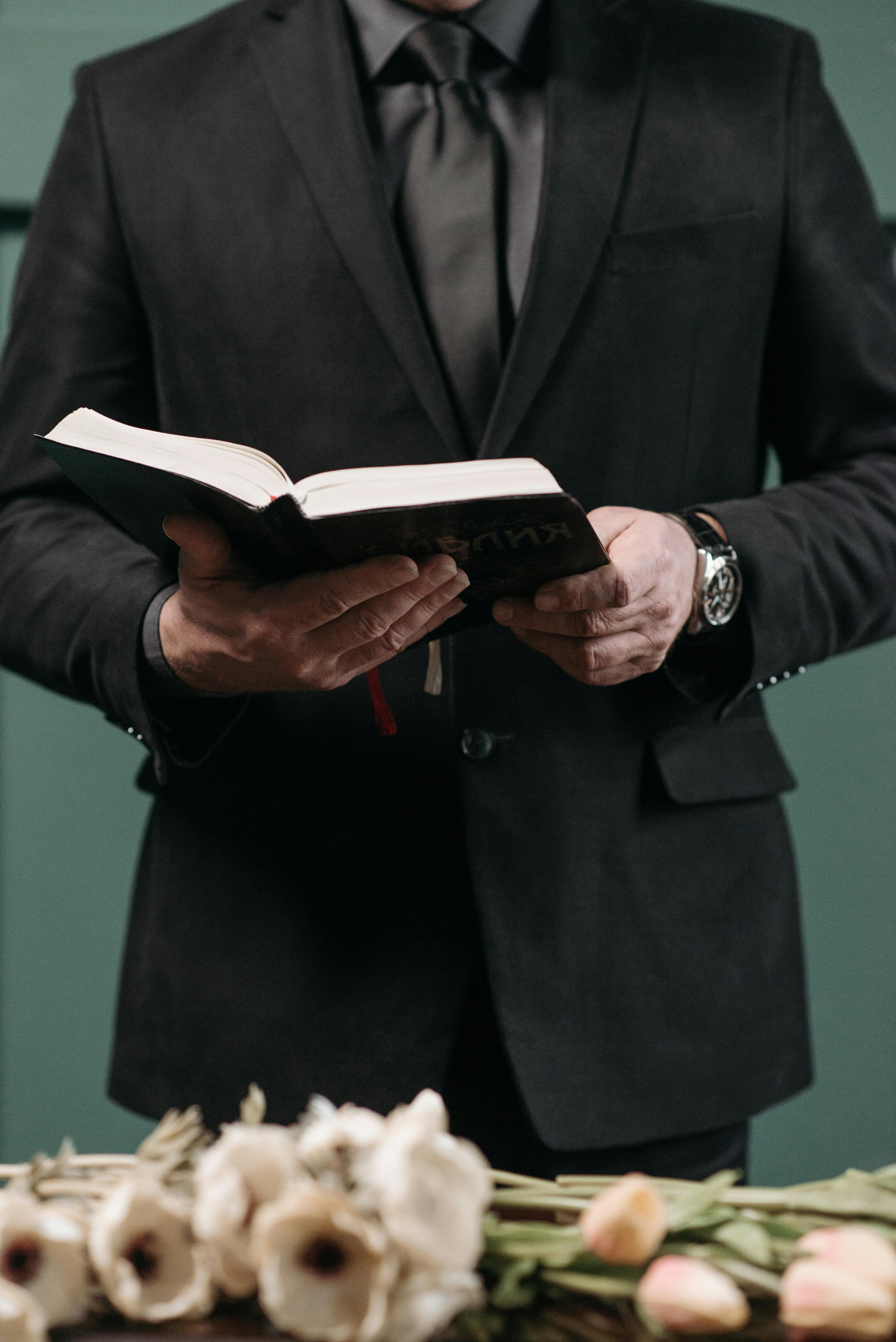 A Man in Black Suit Holding an Open Book · Free Stock Photo