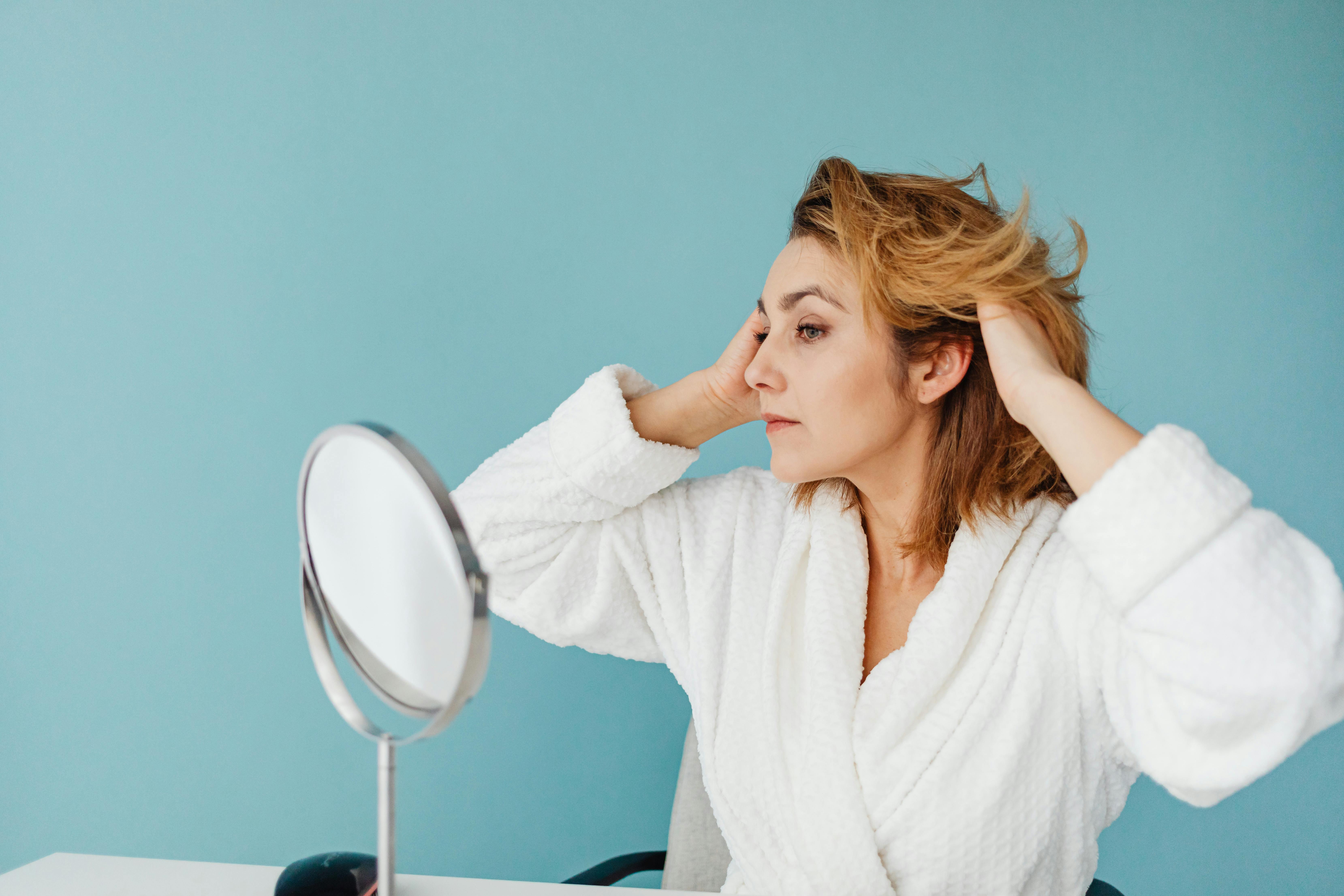 A Woman Fixing Her Hair while Looking at a Mirror · Free Stock Photo