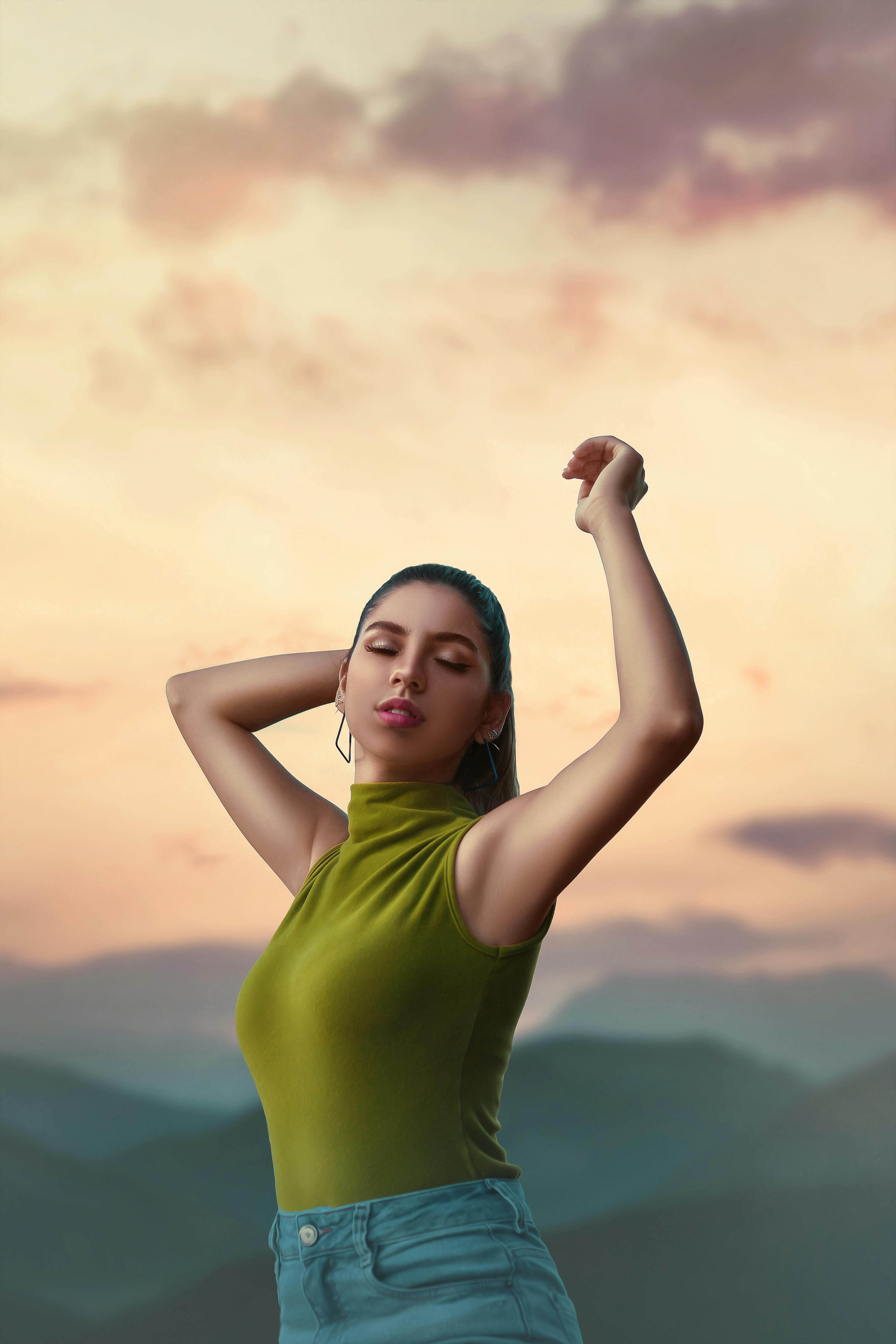 Stylish woman standing with raised arms against mountains · Free Stock ...