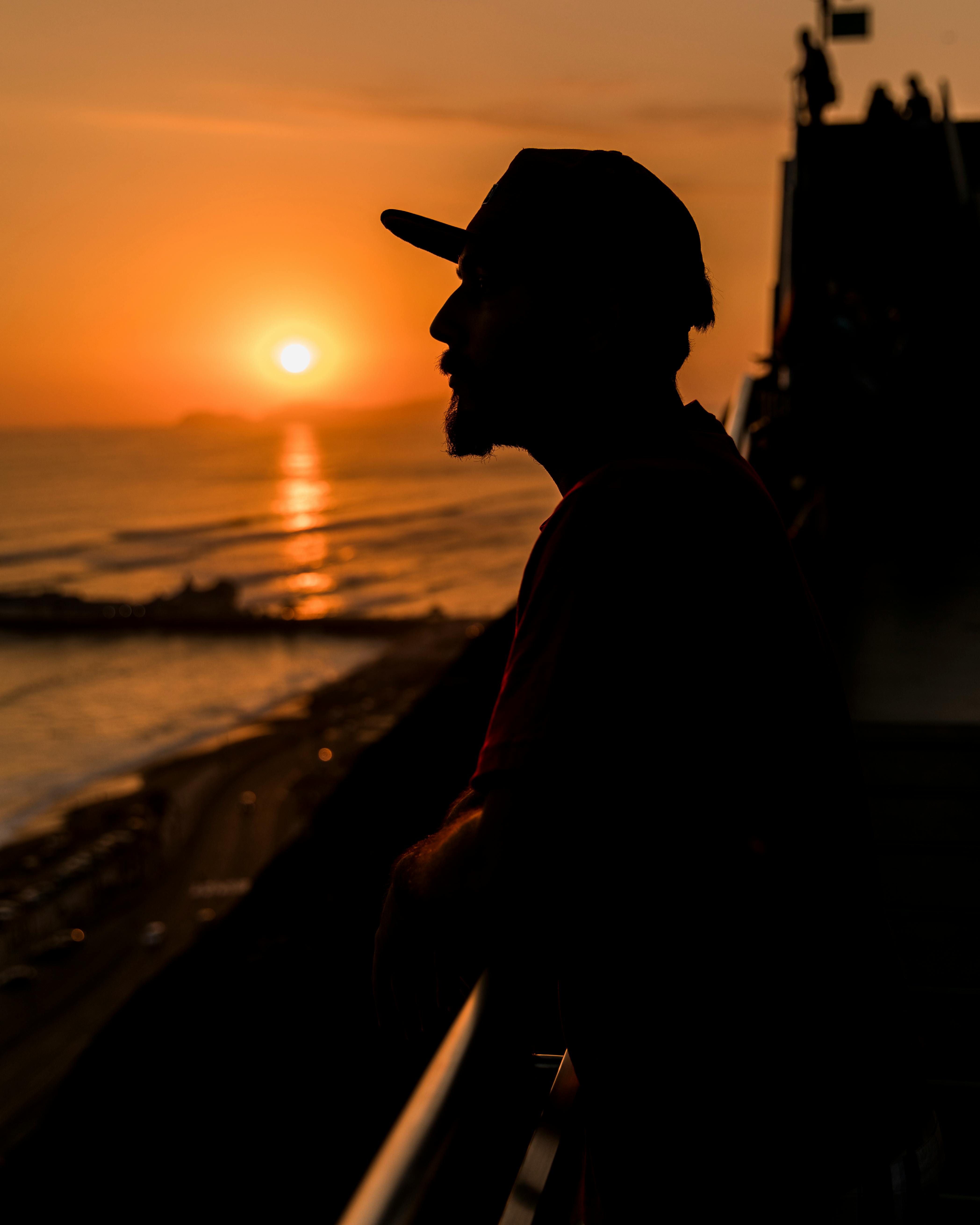 A Man Standing Beside a Railing Looking Afar during Sunset · Free Stock ...