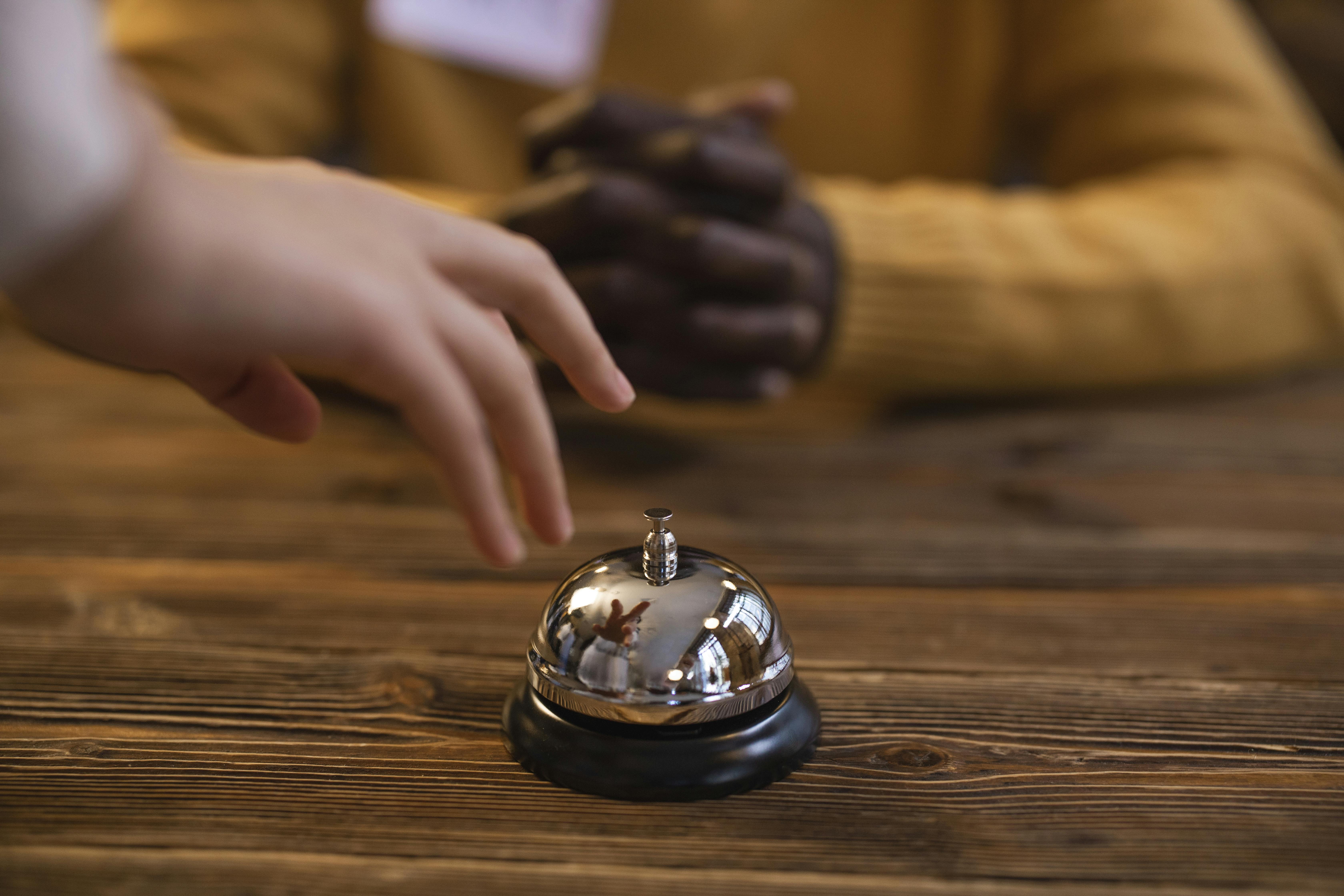 A Silver Reception Bell on the Wooden Table · Free Stock Photo