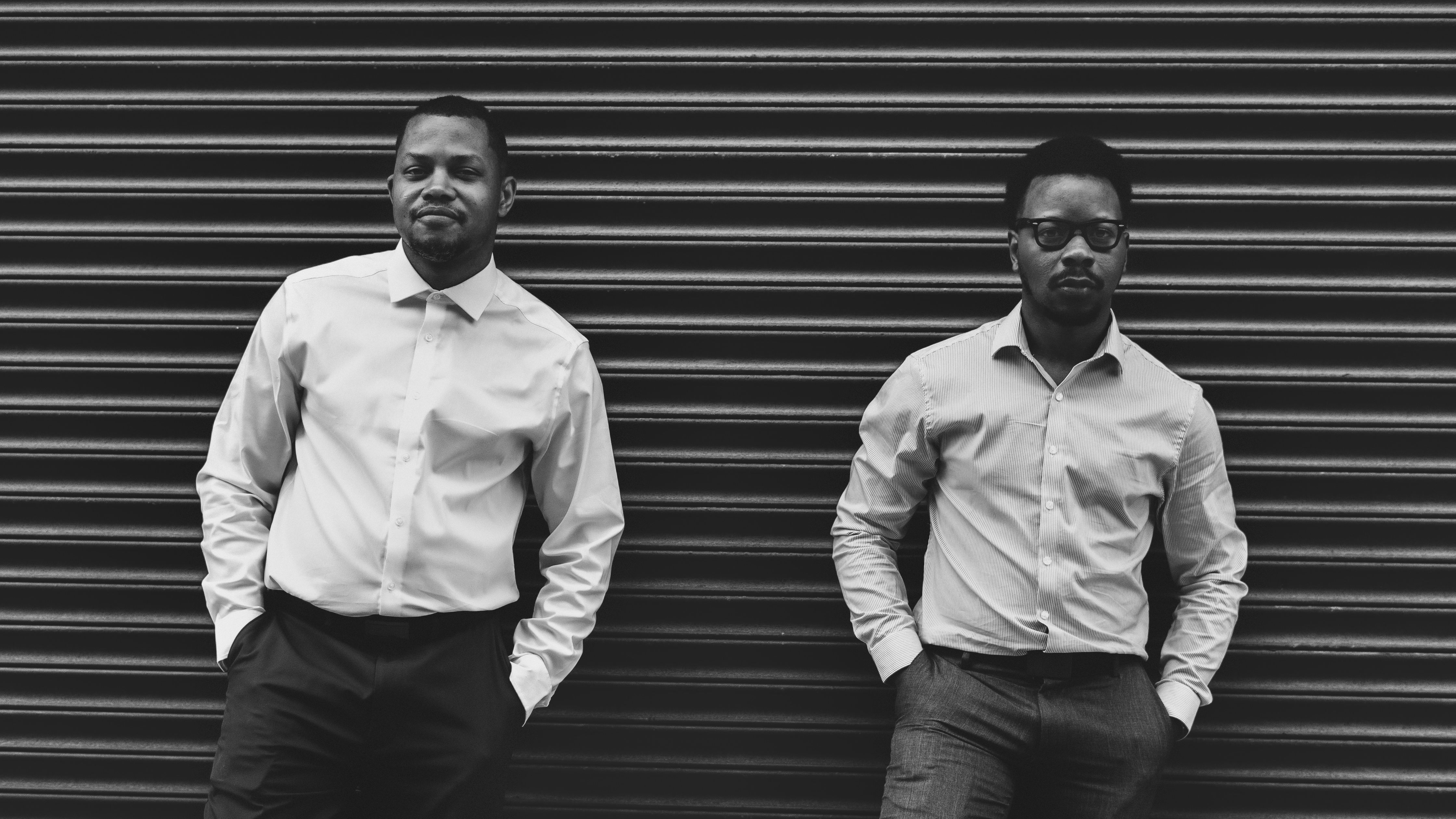 Stylish black man sitting on stone border · Free Stock Photo
