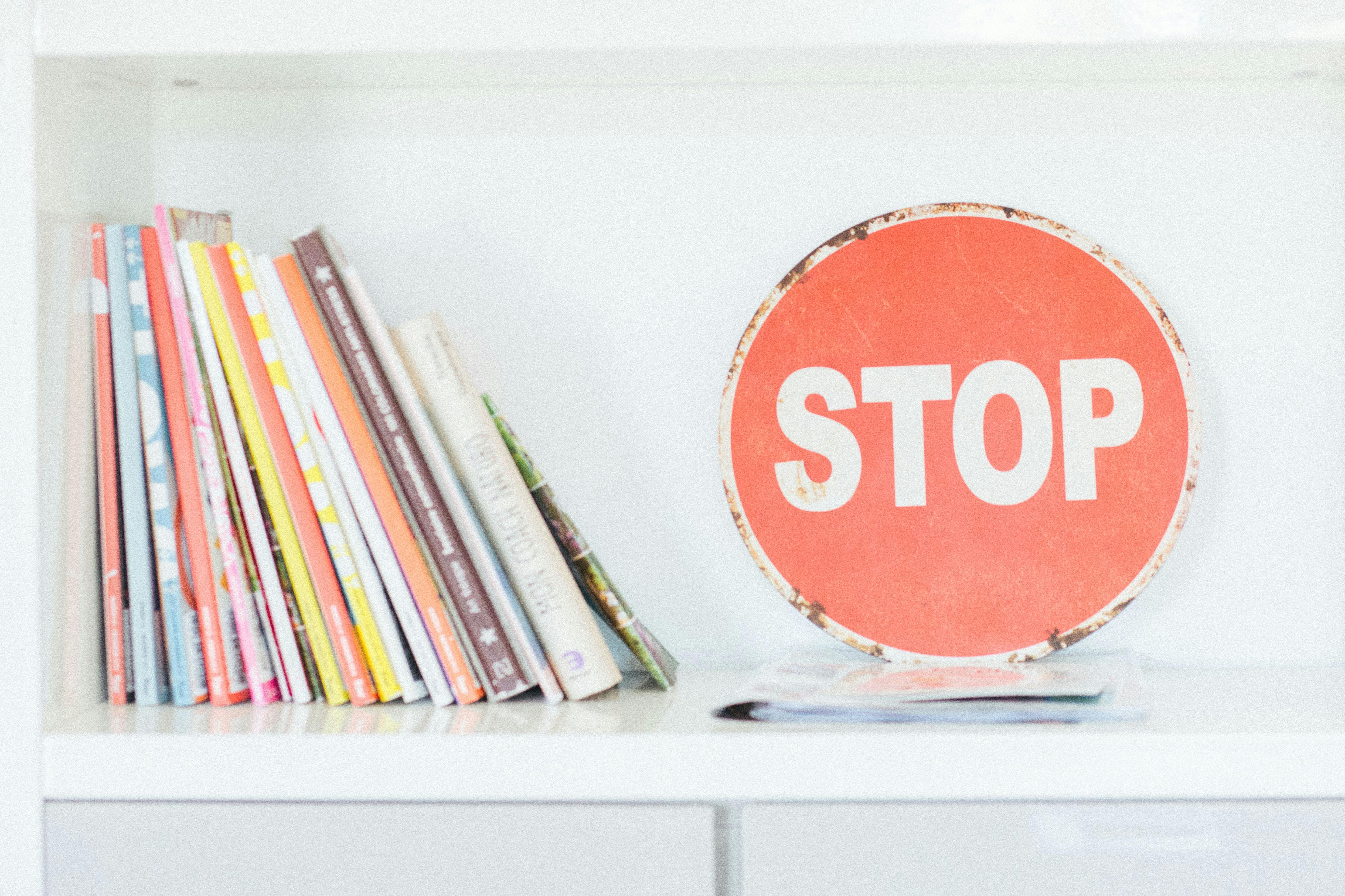 Round Stop Sign and School Textbooks on Shelf · Free Stock Photo