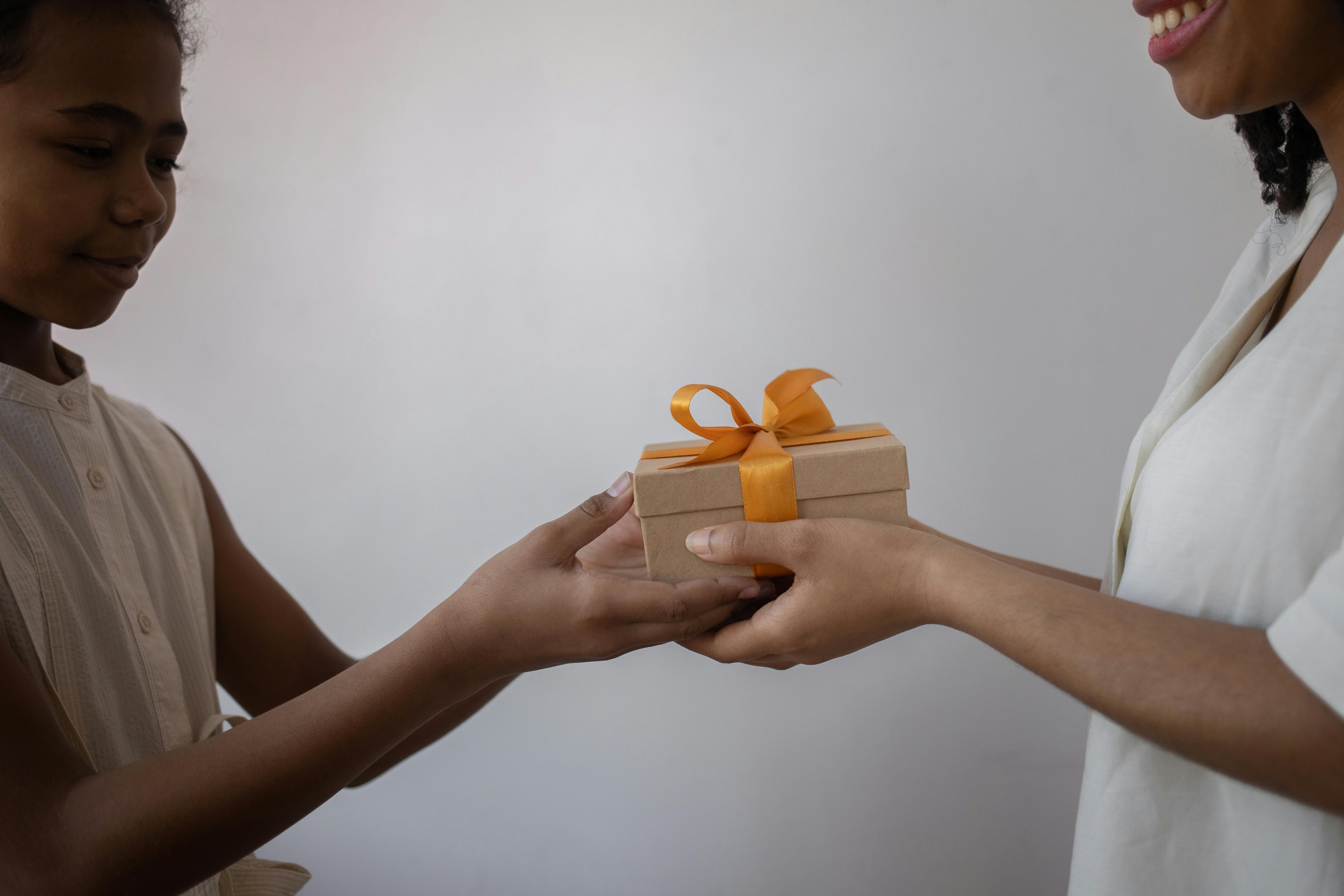 A Girl Handing a Gift Box With Ribbon to a Woman · Free Stock Photo
