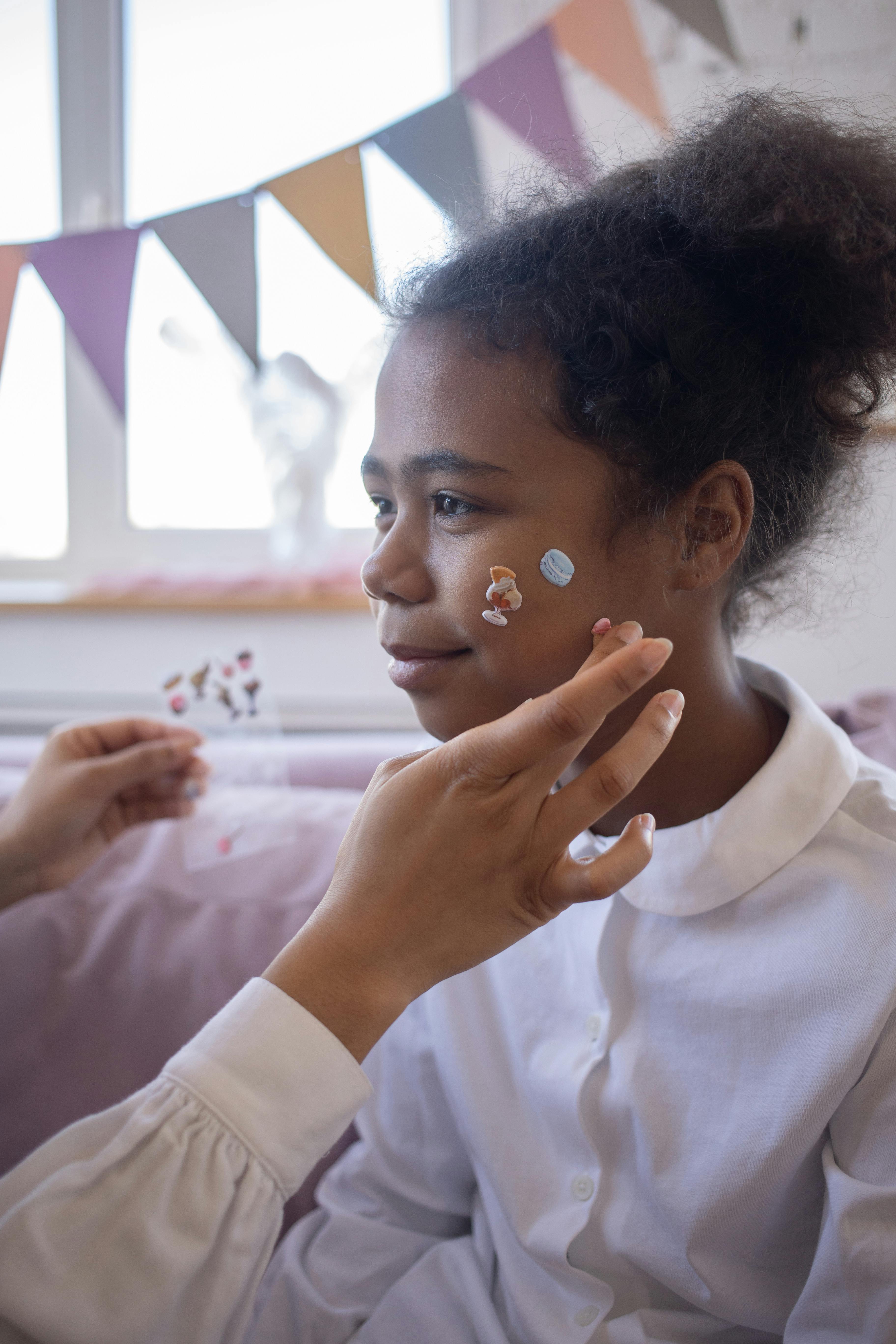 A Person Putting Stickers on the Girl's Face · Free Stock Photo