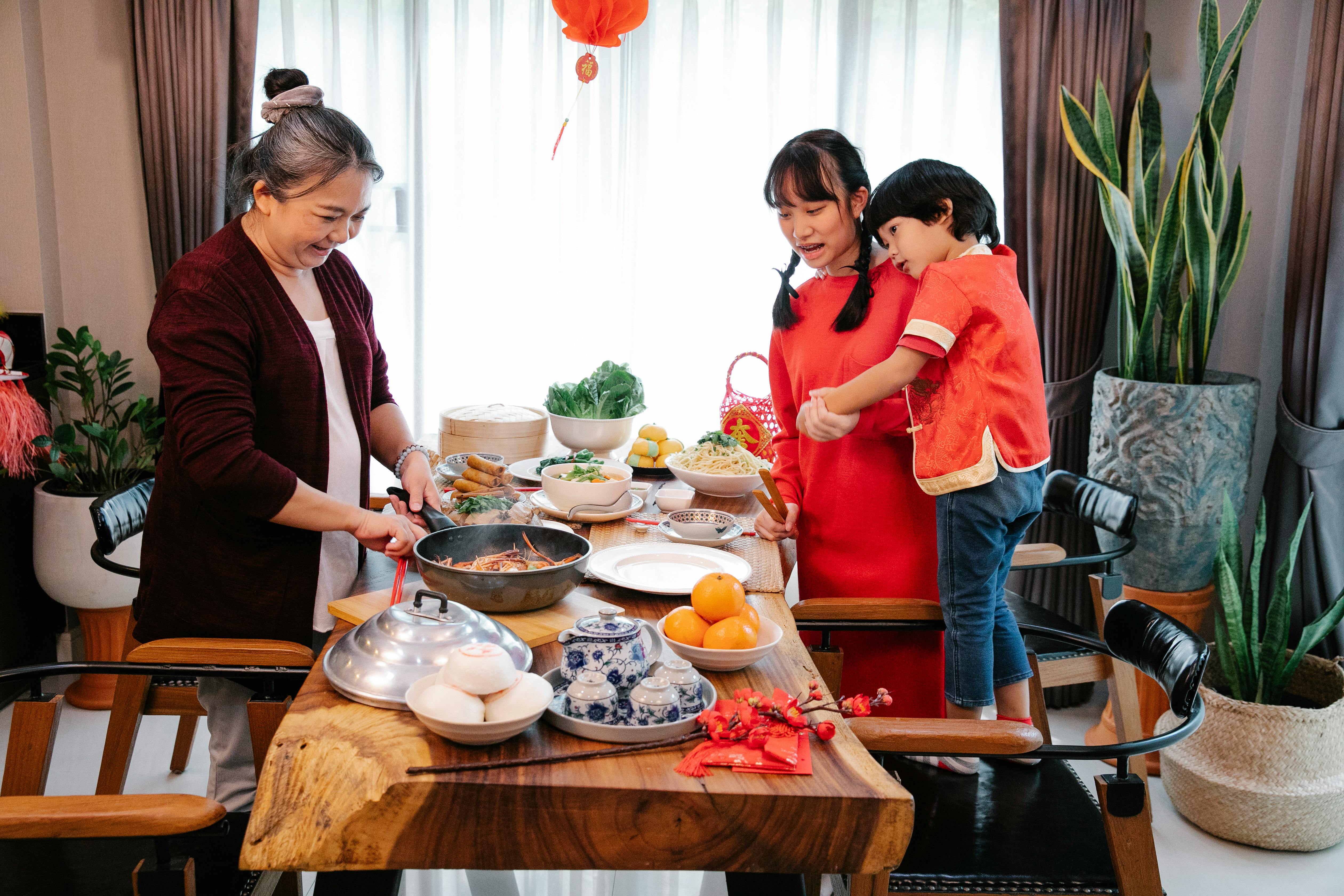 Positive Asian woman cooking Chinese food for festive occasion · Free ...