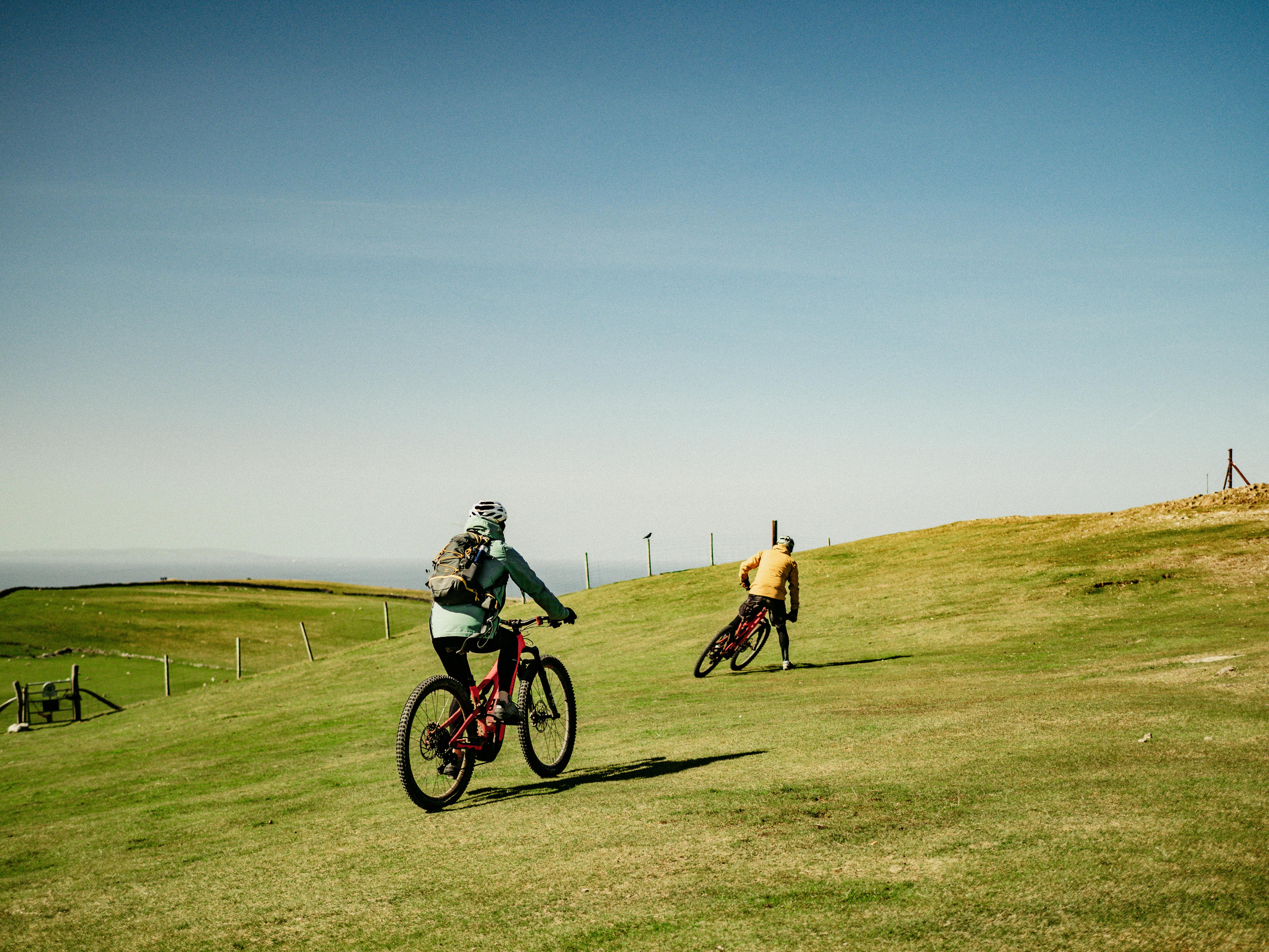 Two Bikers Riding a Bike on a Grassy Field · Free Stock Photo