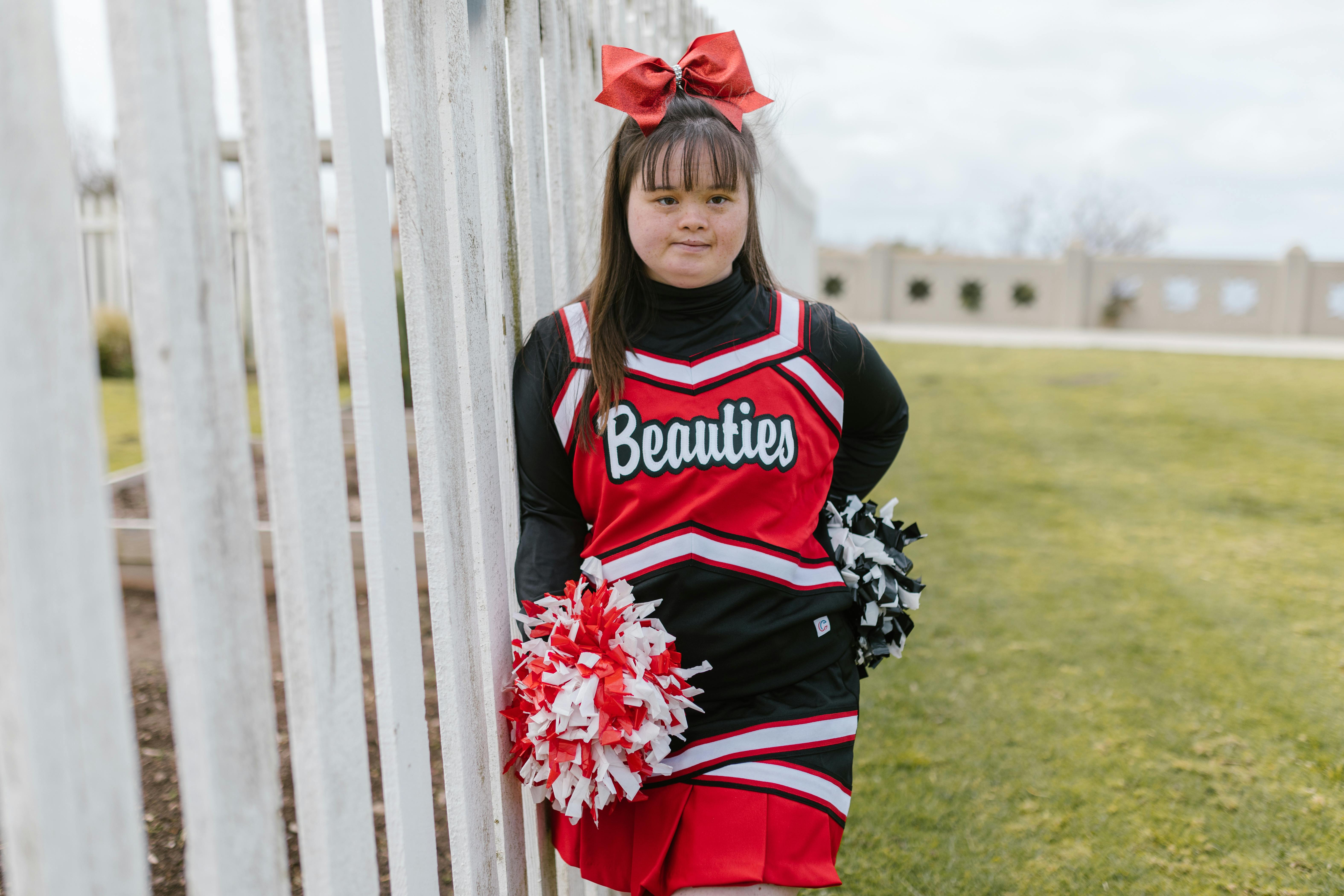 Woman in Cheerleader Outfit Standing beside Wooden Fence · Free Stock Photo