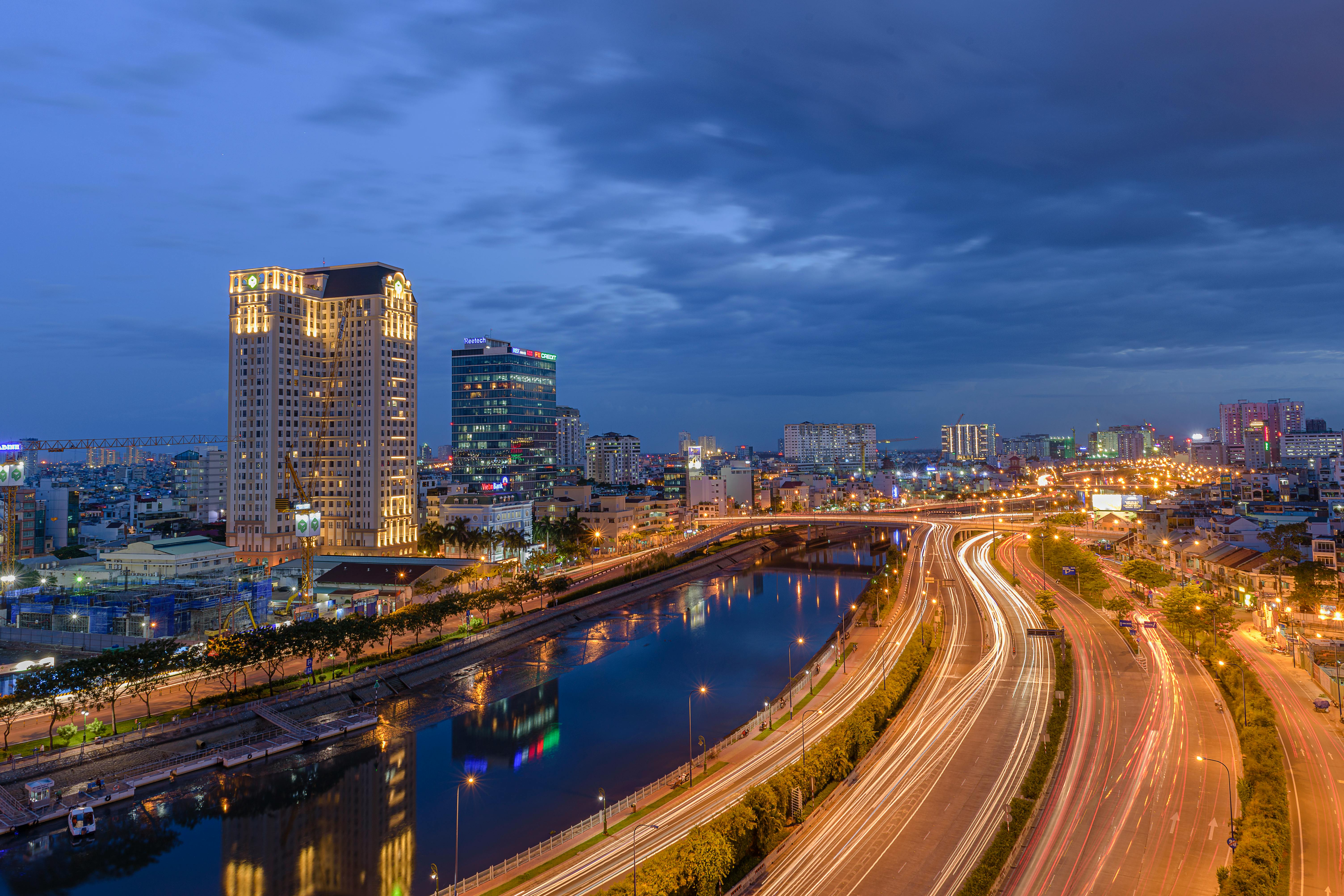 Illuminated modern city with river and roads in twilight · Free Stock Photo