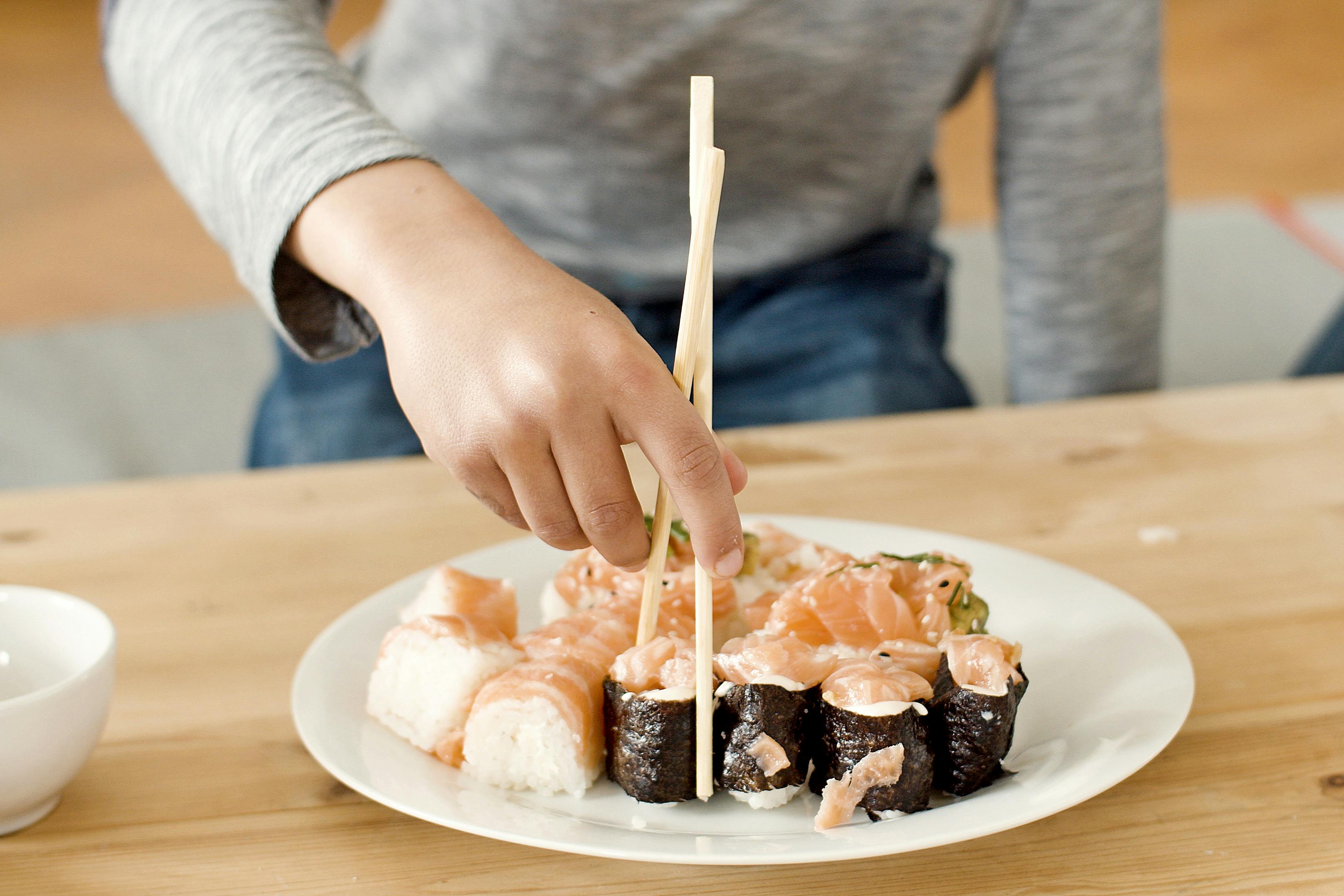 Hand Getting Sushi Using Wooden Chopsticks · Free Stock Photo