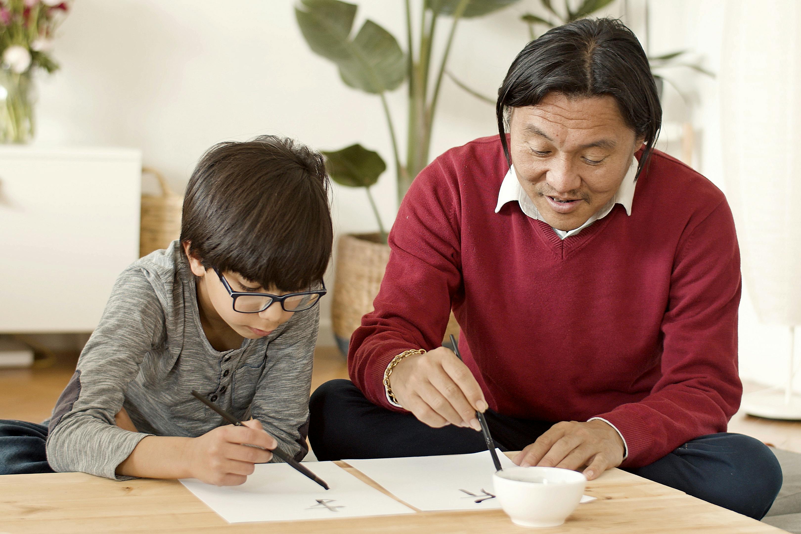A Boy with his Father Writing on Paper · Free Stock Photo
