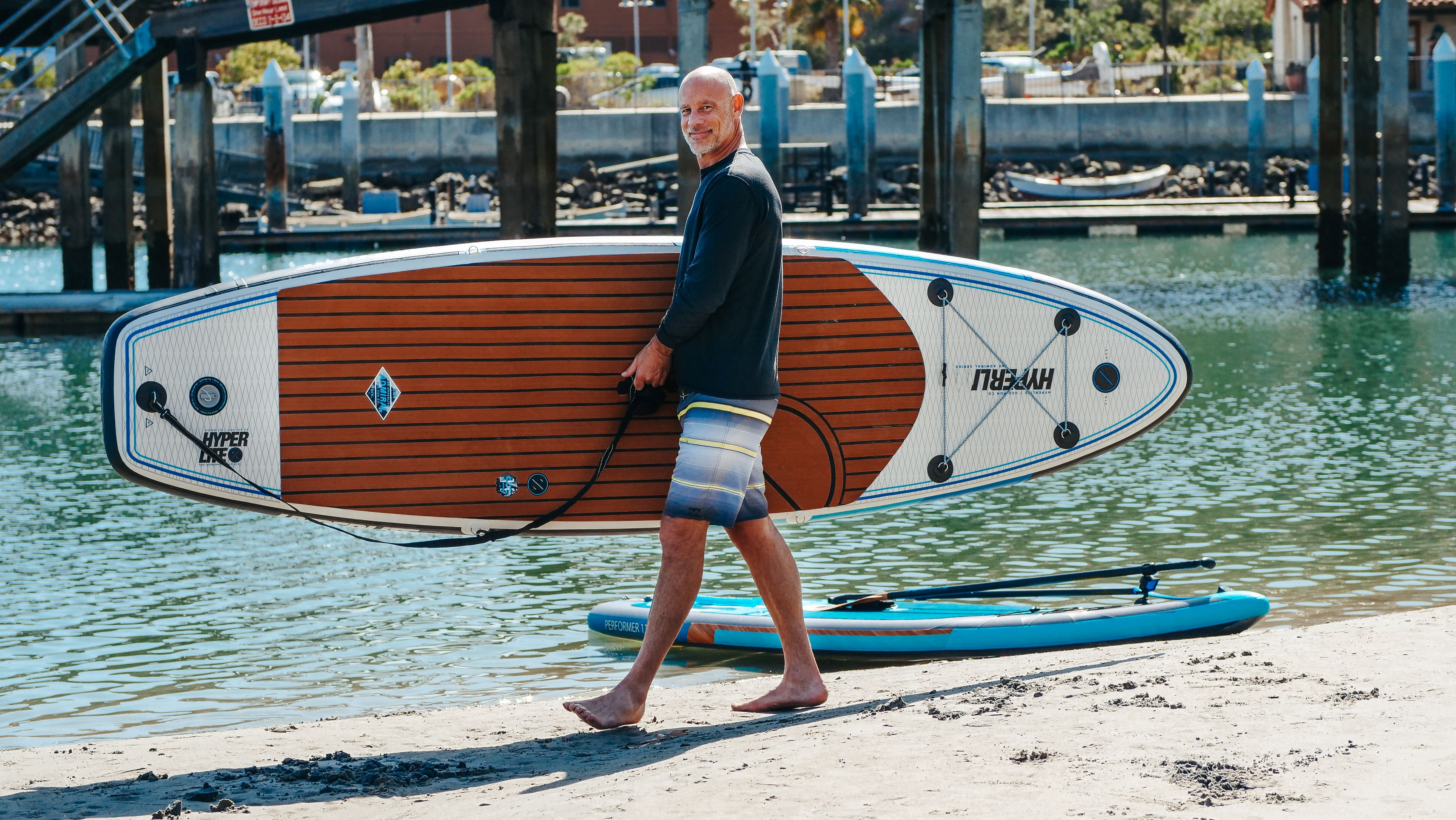 A Man Carrying a Paddleboard · Free Stock Photo