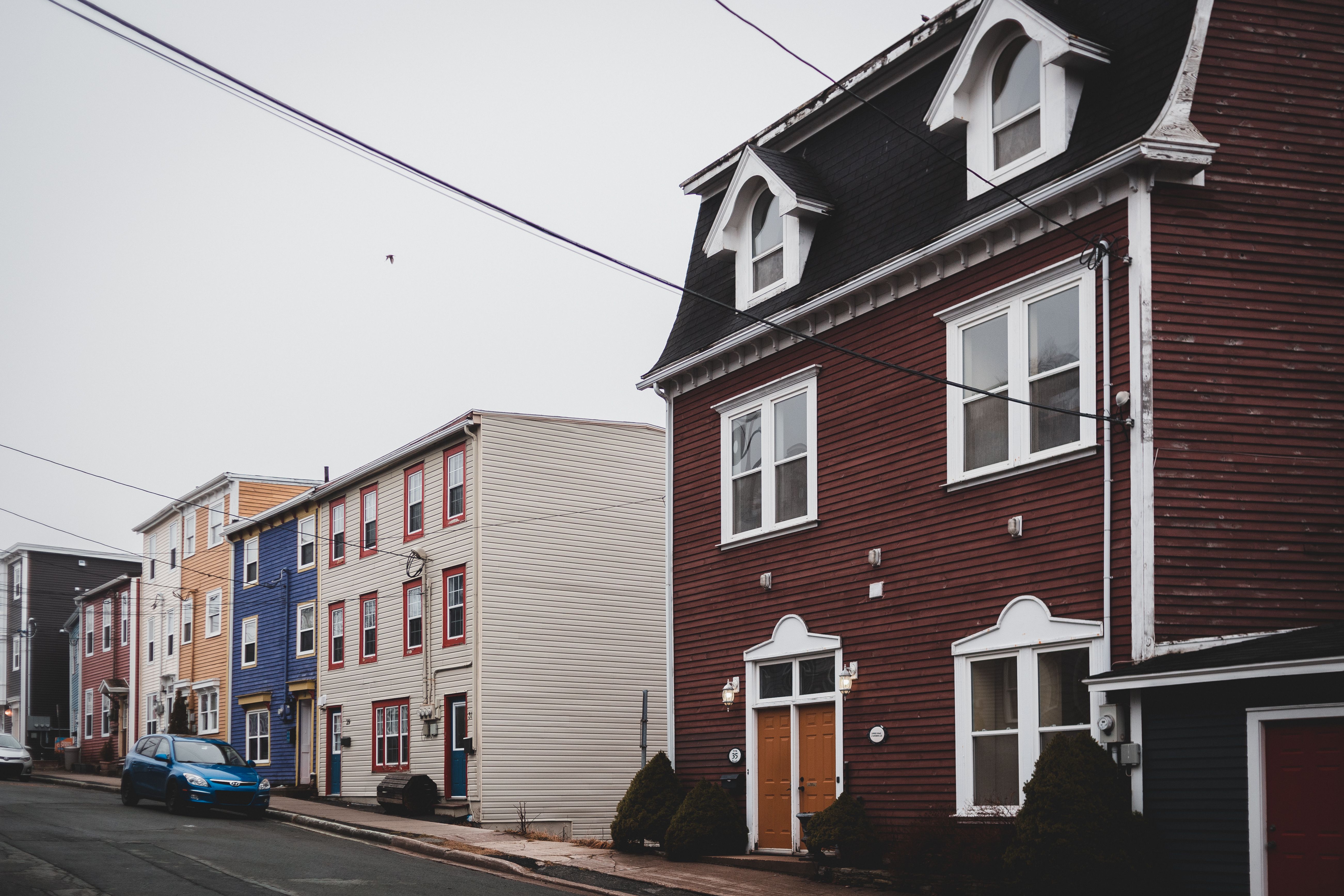 Old residential houses and car driving on road · Free Stock Photo