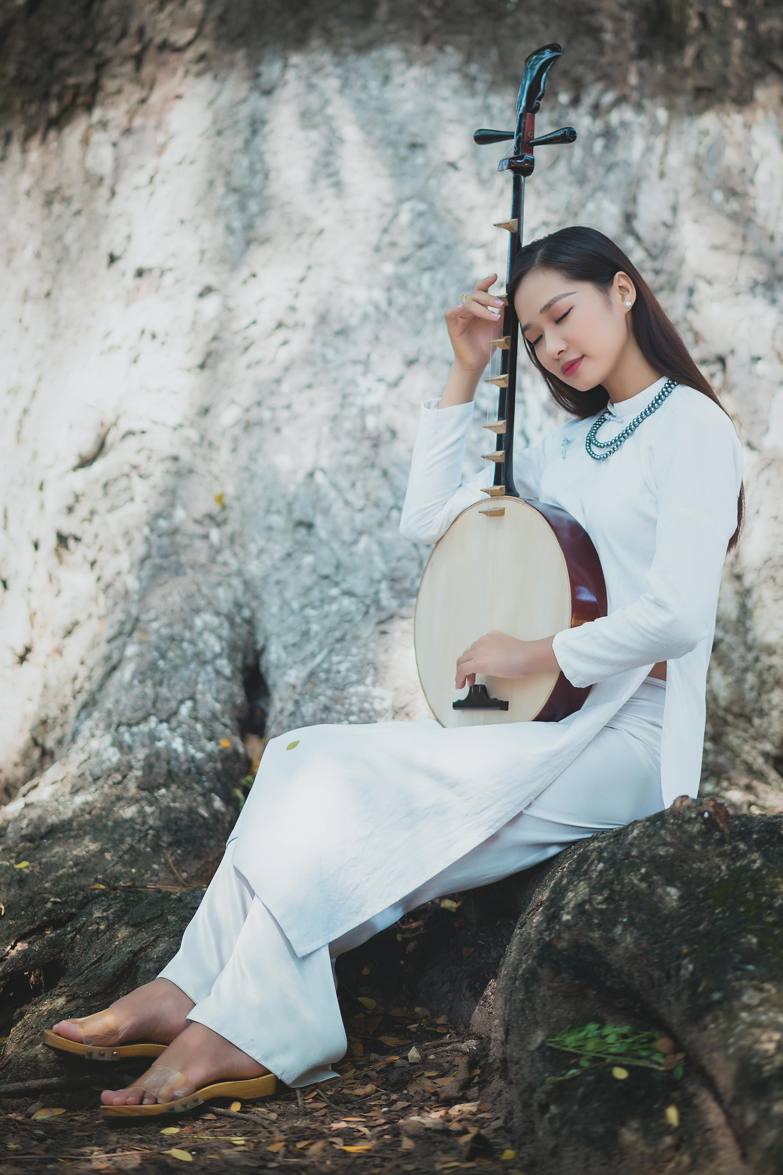 Asian female playing ruan while sitting on ground · Free Stock Photo