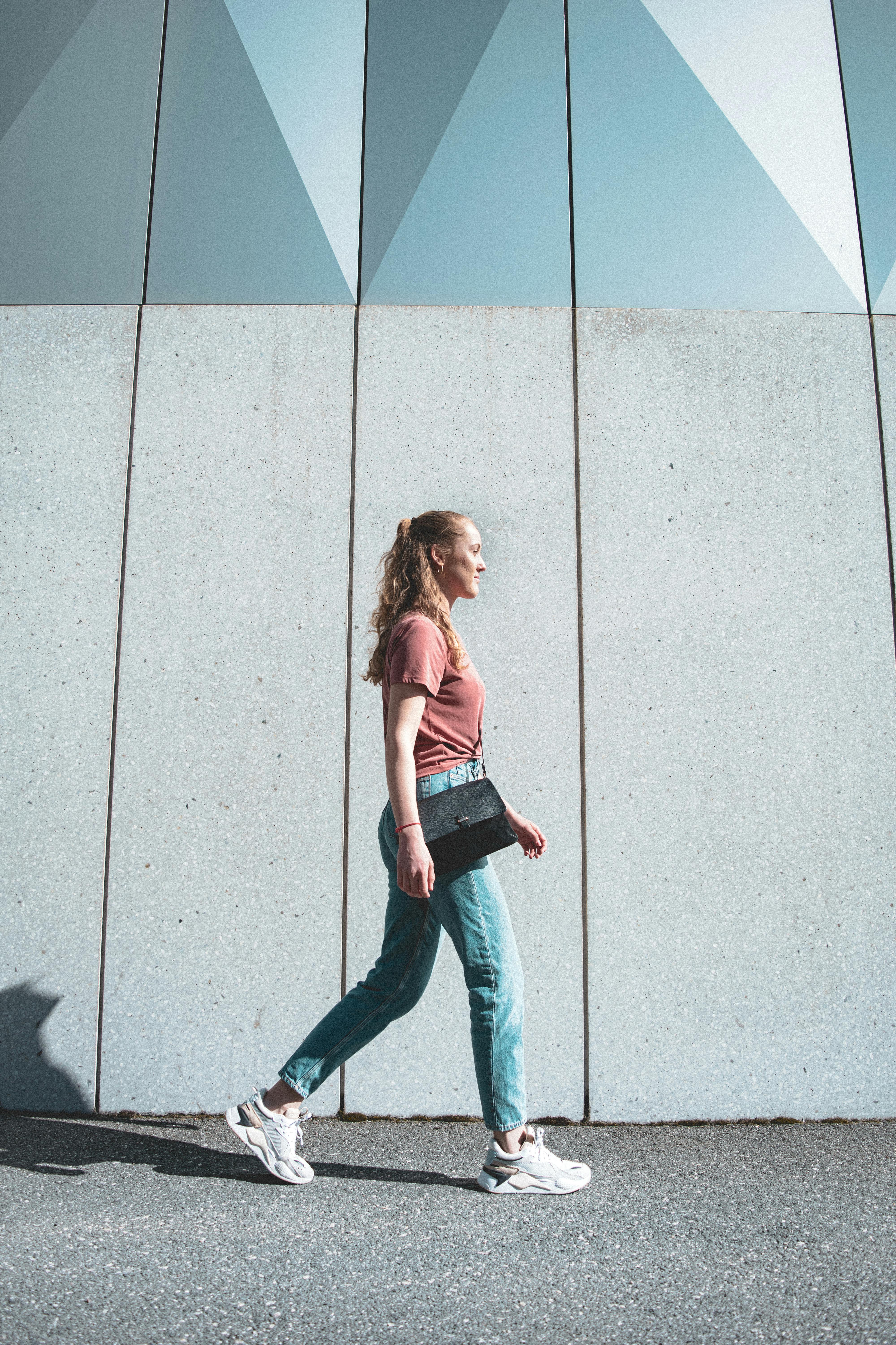 A Woman in Brown Top and Denim Jeans Walking on the Sidewalk · Free ...