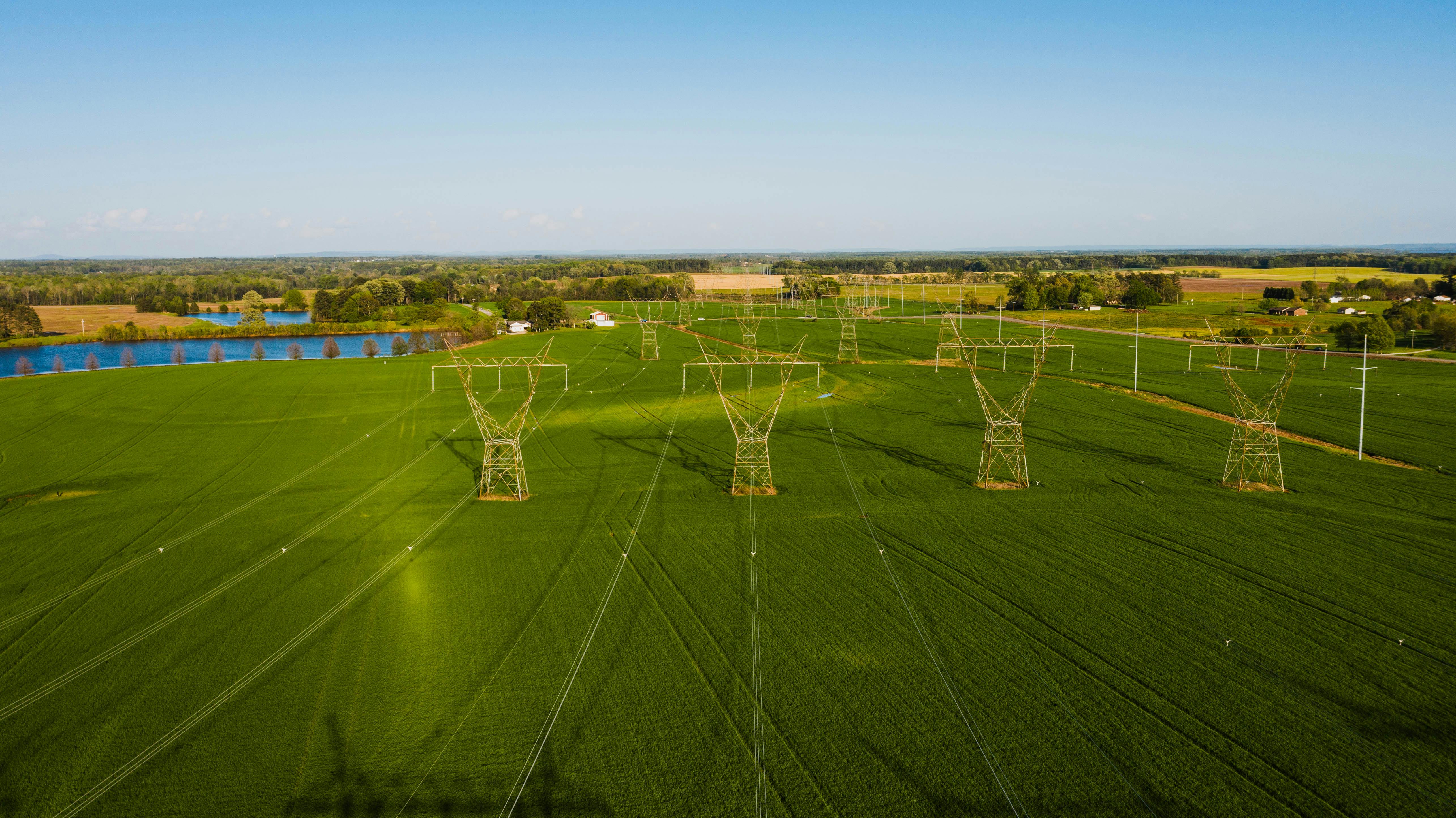 Endless meadow with fresh green grass and power station · Free Stock Photo
