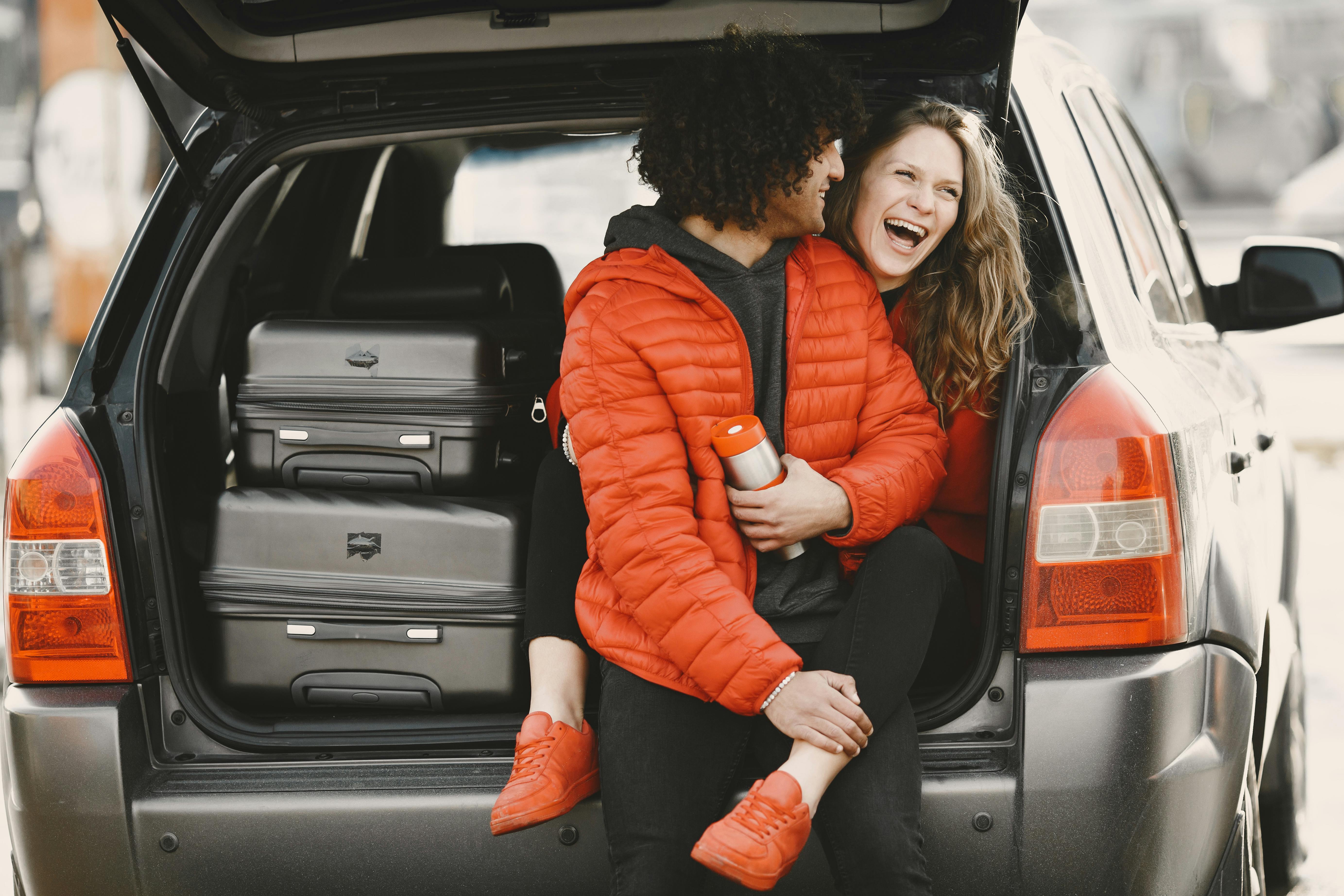 Man in Red Coat Standing Beside Woman Sitting in Car Trunk · Free Stock ...