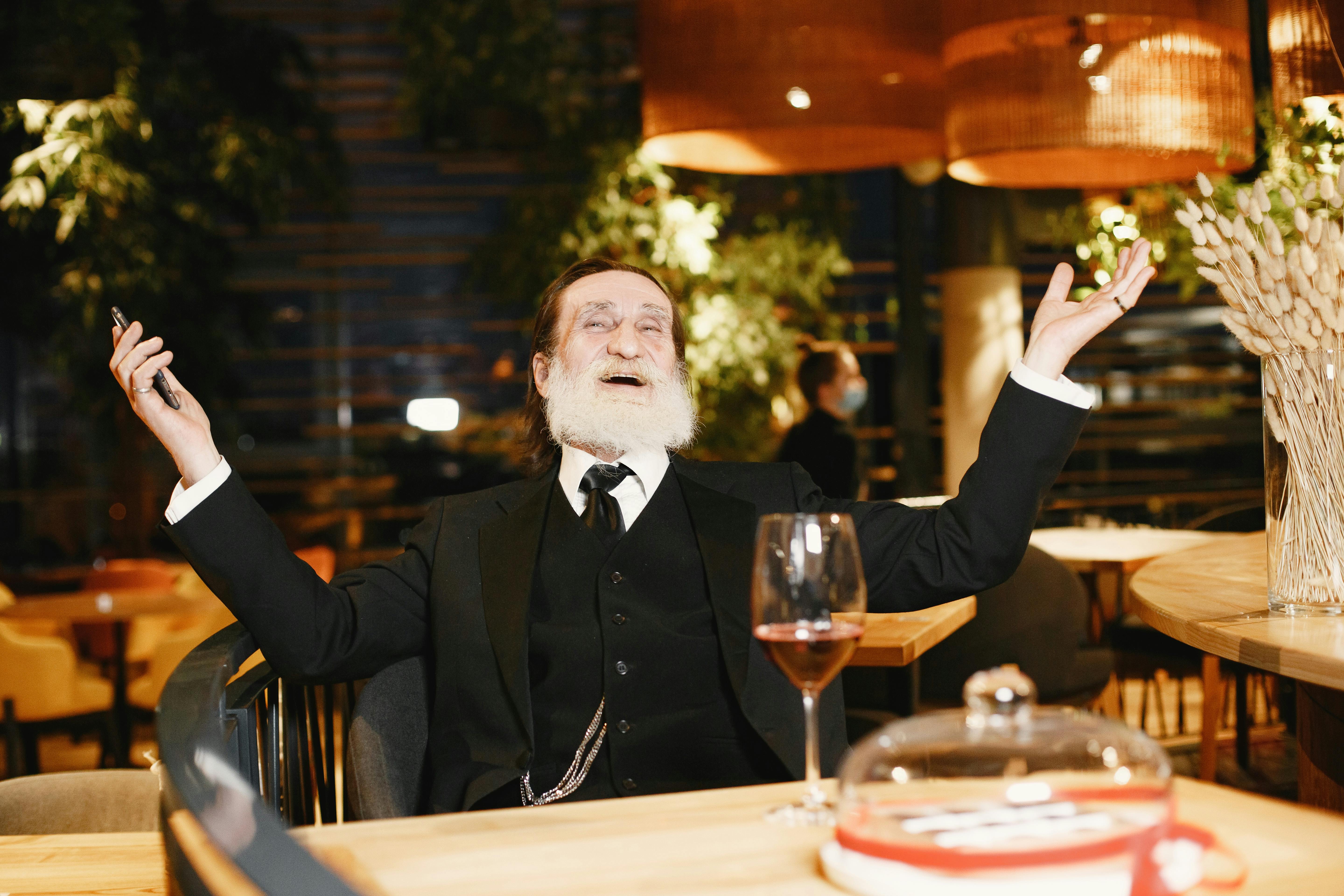 A Happy Man Sitting on a Chair in Front of a Wooden Table with Wine ...