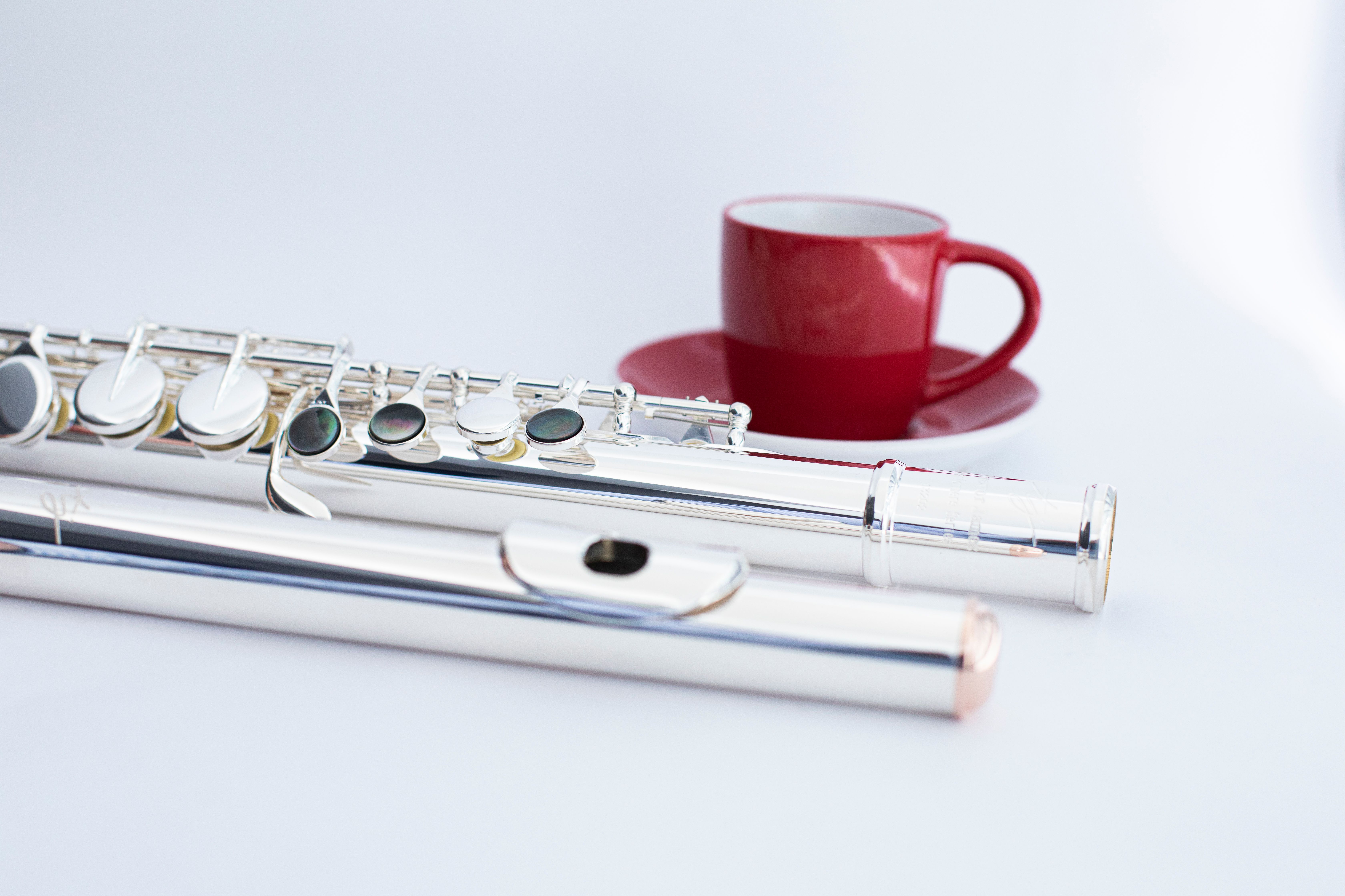 Red Ceramic Cup and Saucer Near a Silver Flute · Free Stock Photo