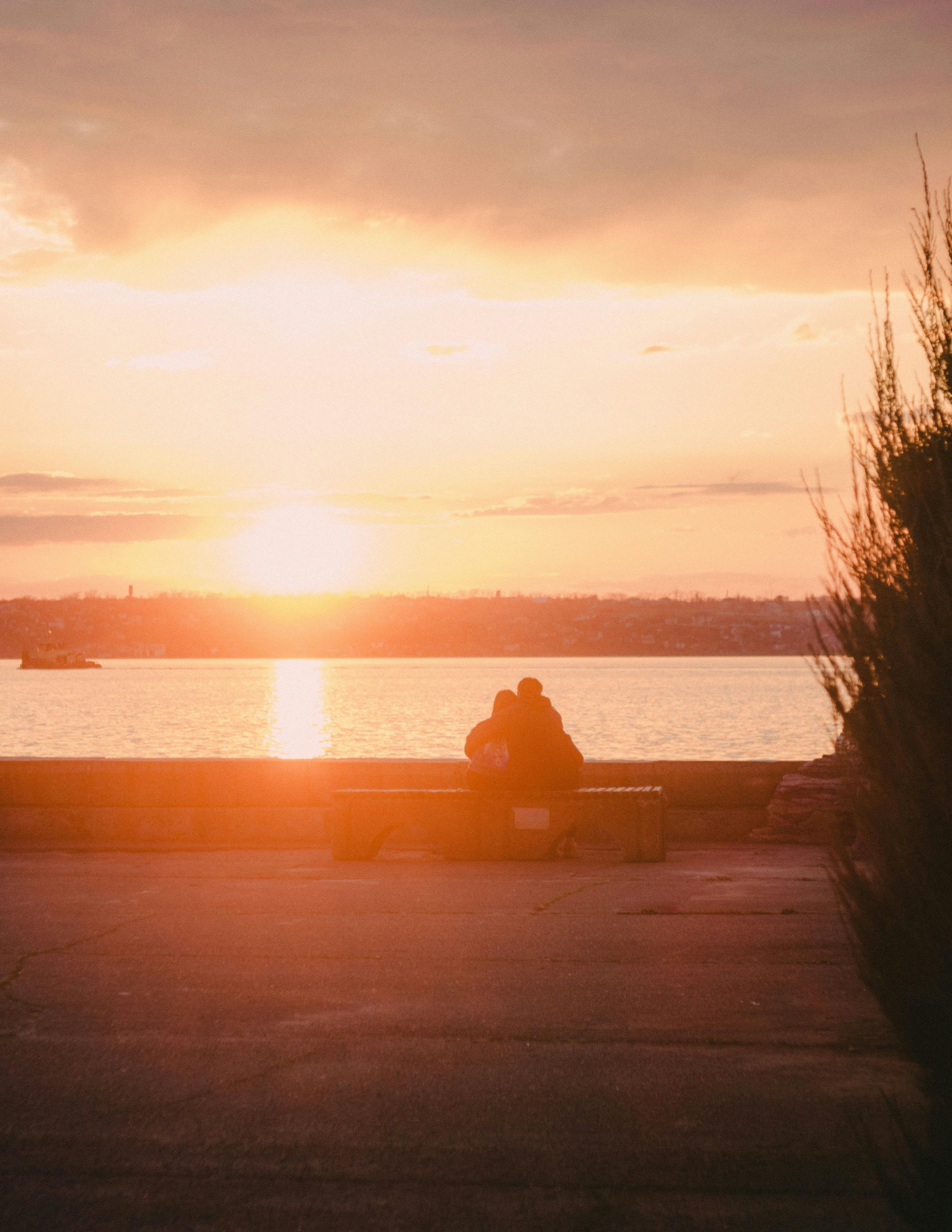 Silhouette of Couple Sitting on Bench during Sunset · Free Stock Photo