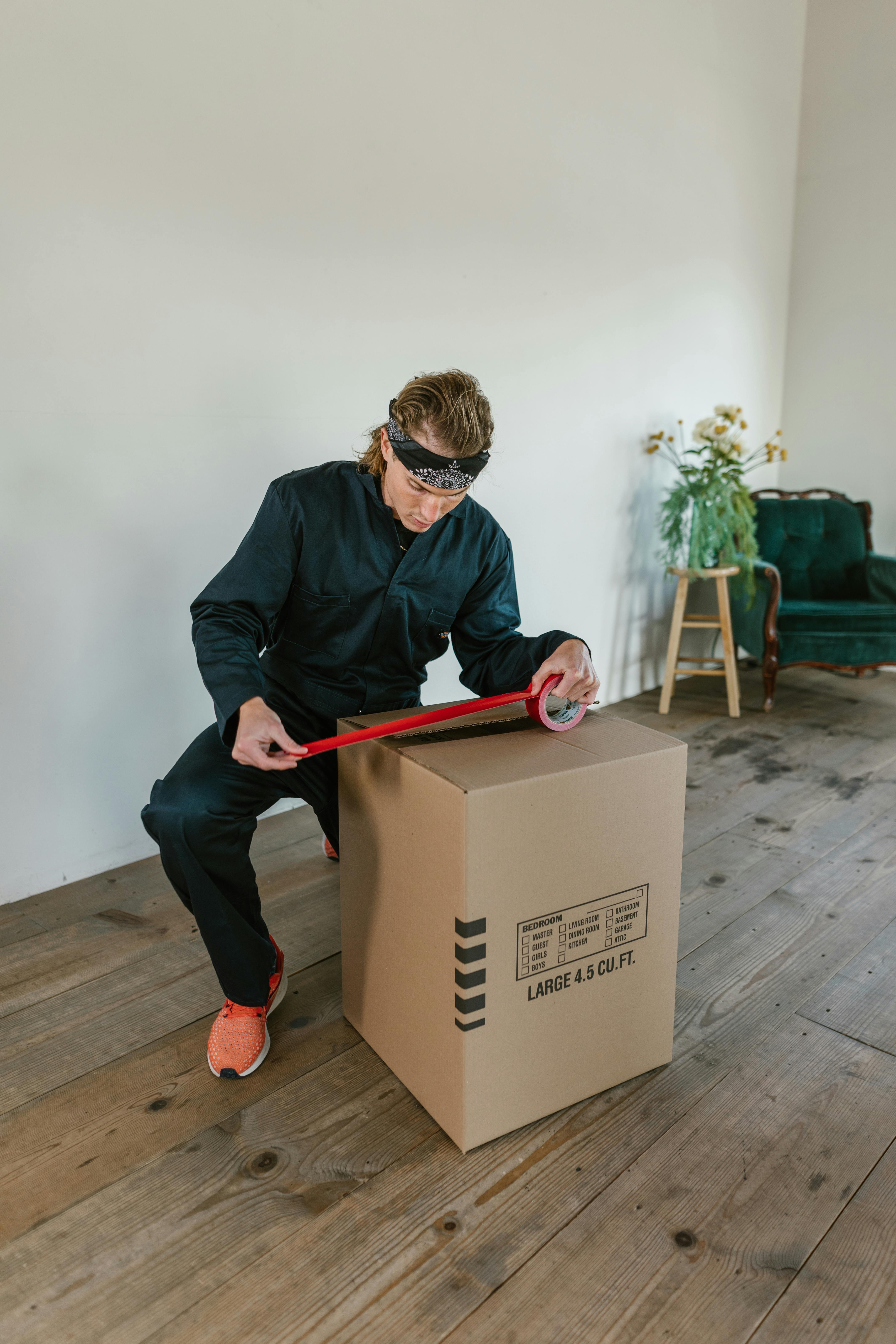 A Man Wrapping a Box Using Adhesive Tape · Free Stock Photo