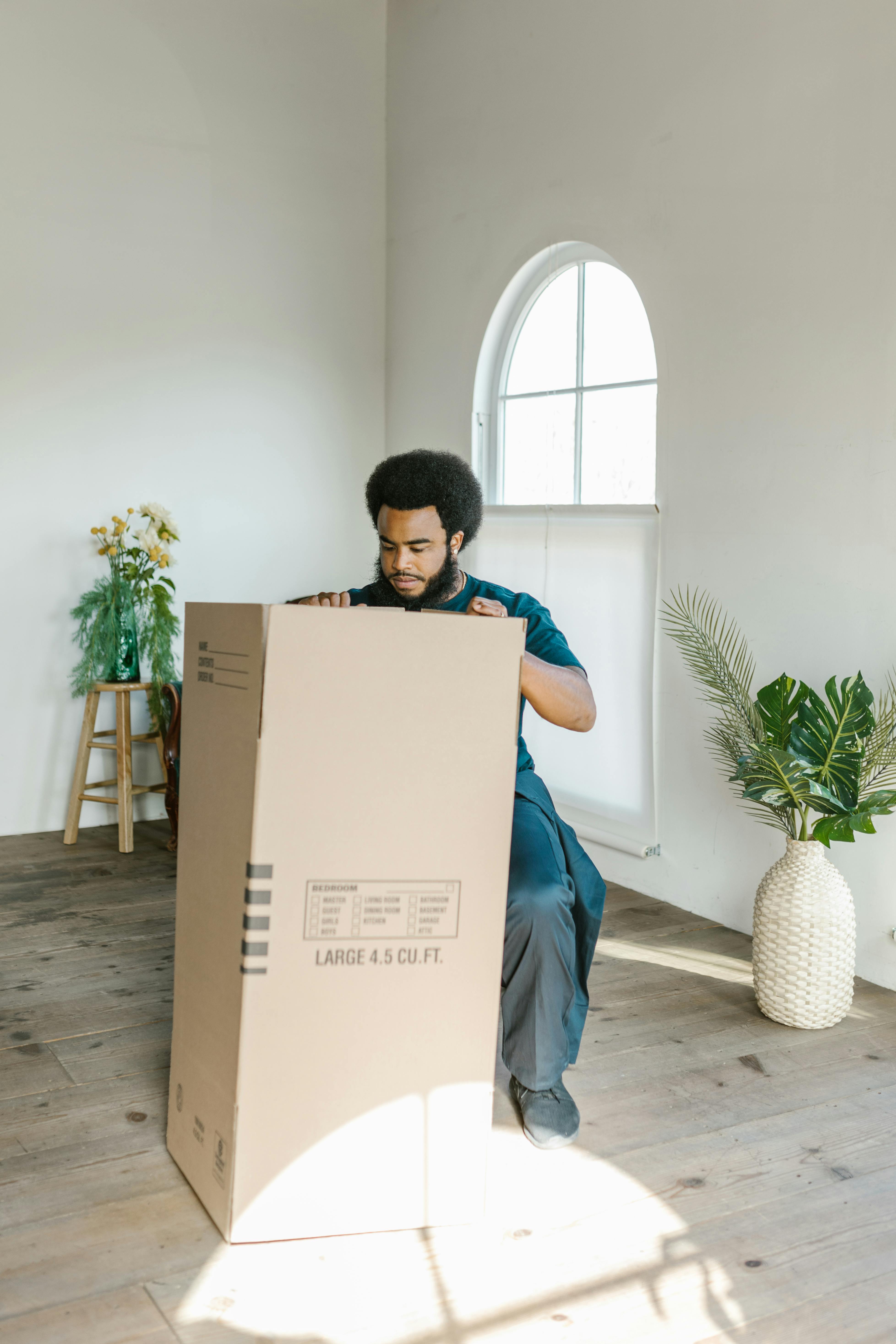 Man Assembling a Brown Cardboard Box · Free Stock Photo