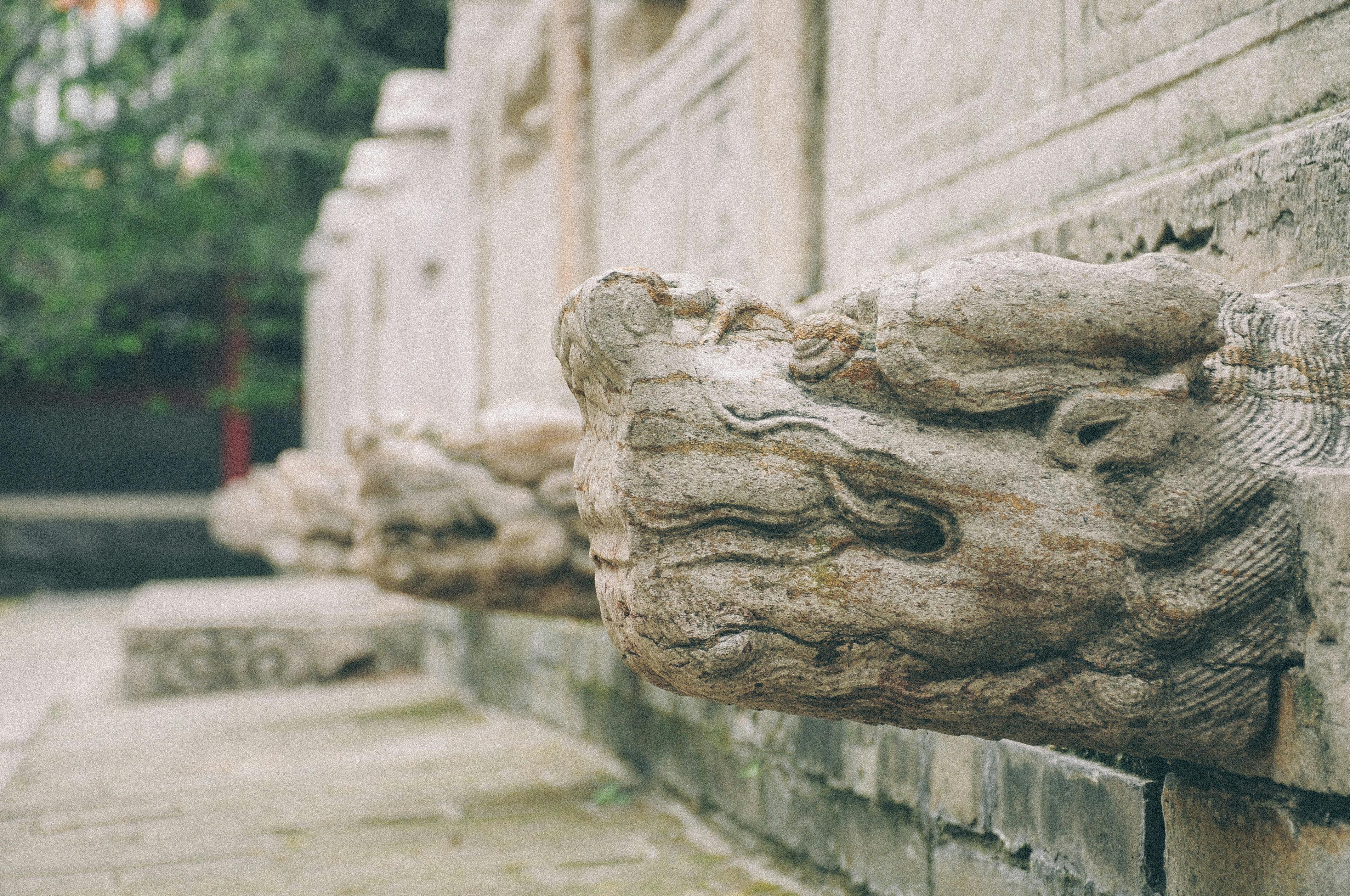 Close-up of Craved in Stone Figures on the Fence · Free Stock Photo