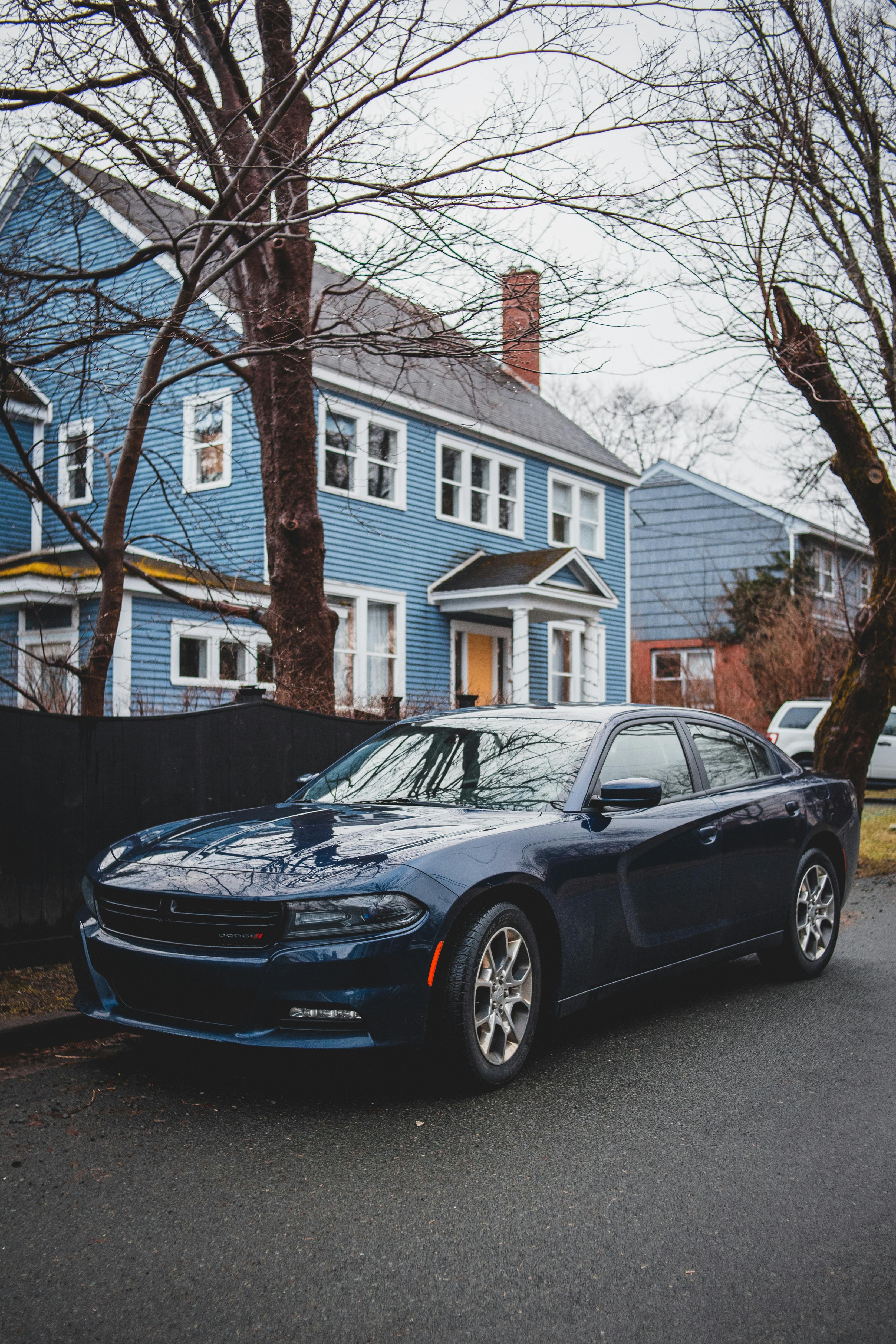 Luxury car parked near fence of residential building · Free Stock Photo